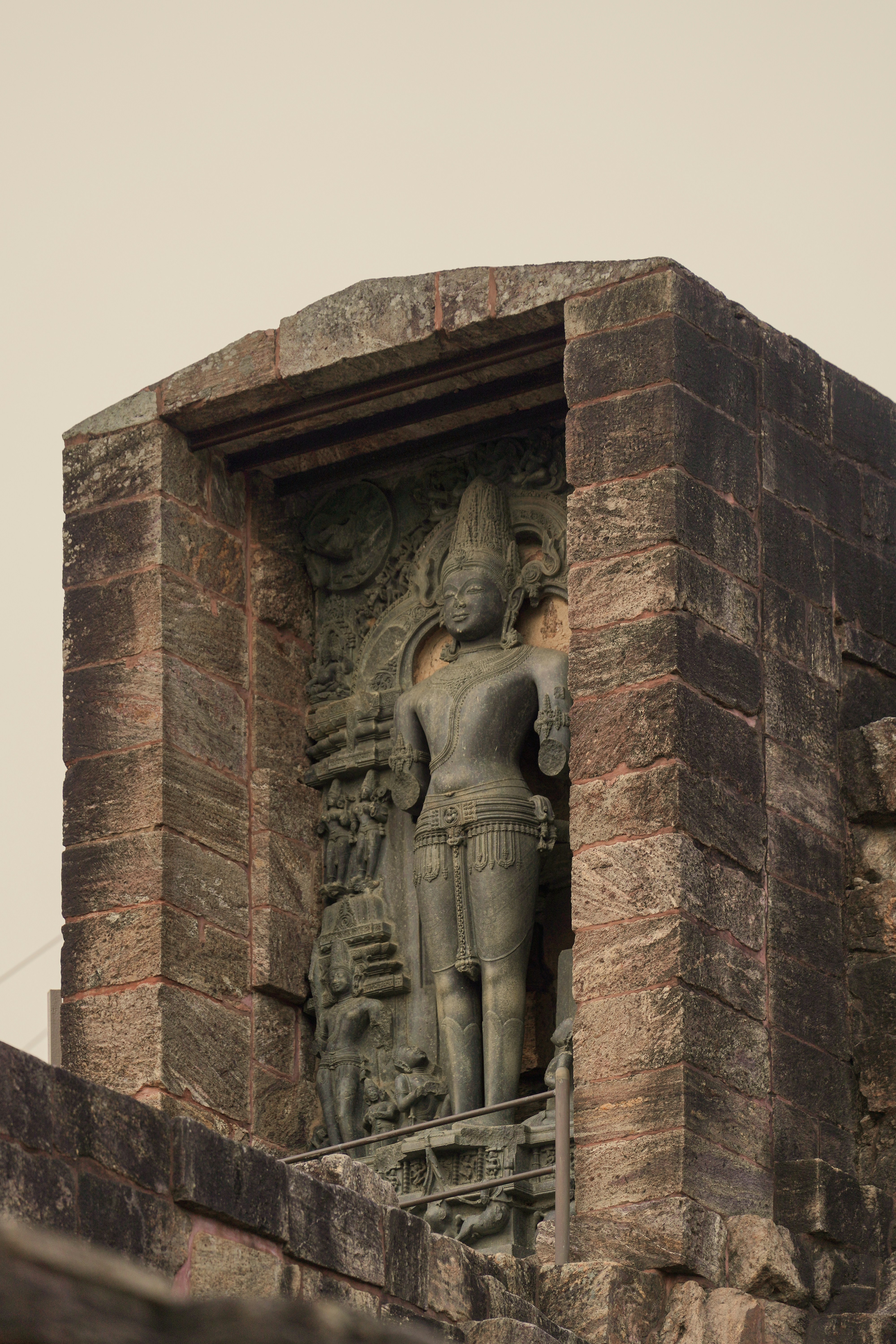 Weathered Sentinel: A Carved Deity in a Crumbling Brick Niche