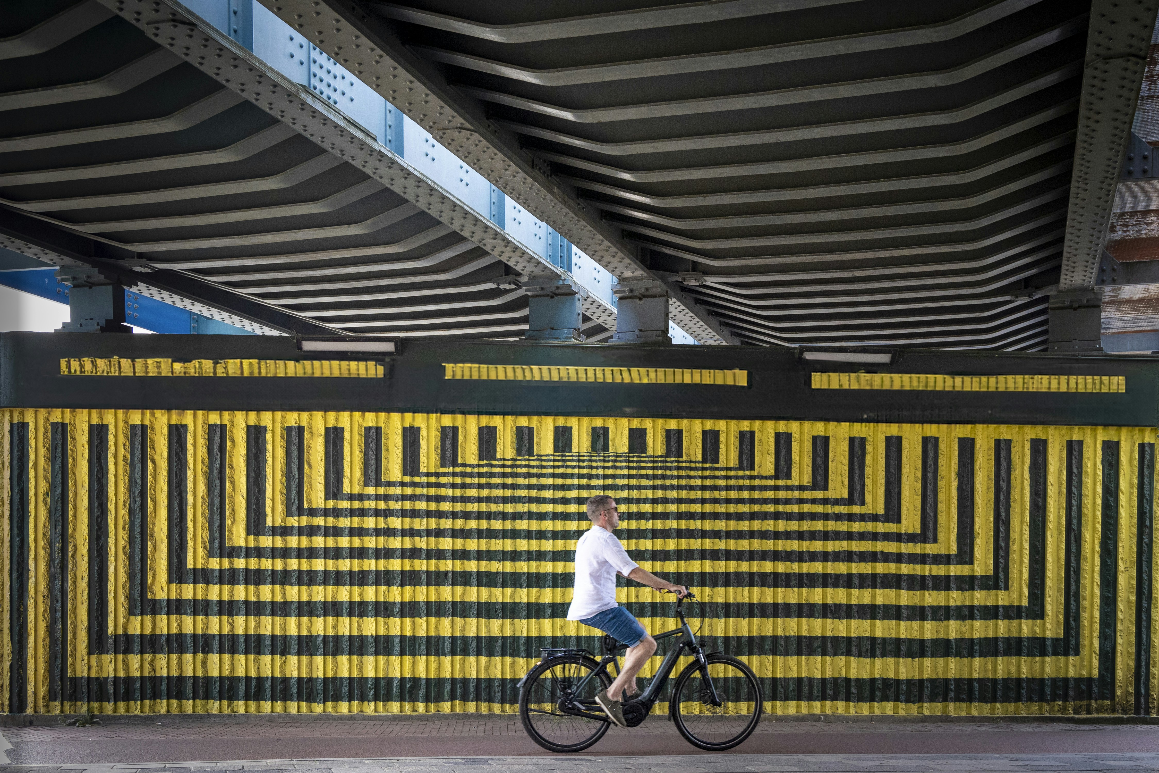 Cyclist under the Bridge: A Bold Geometric Backdrop