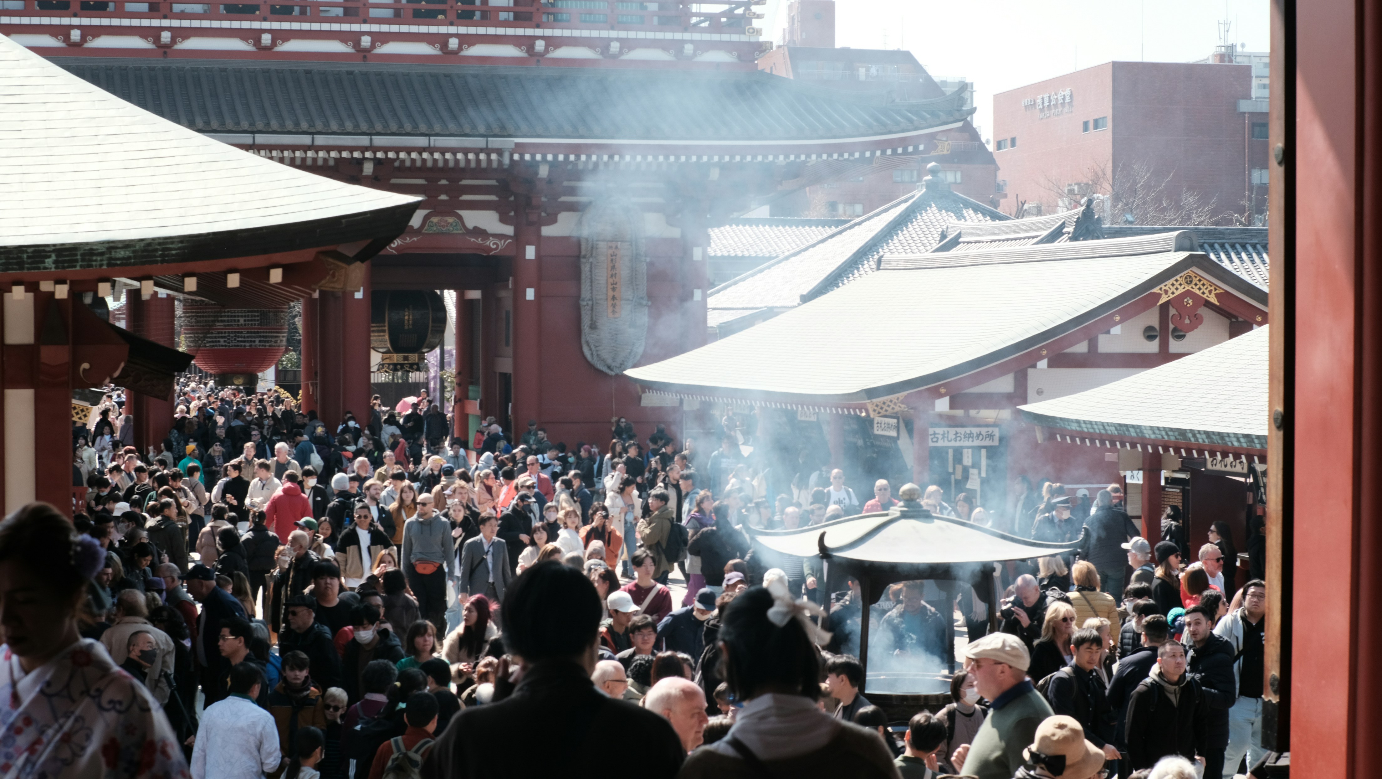 Crowd Beneath Incense Smoke in a Red-Timber Shrine Courtyard