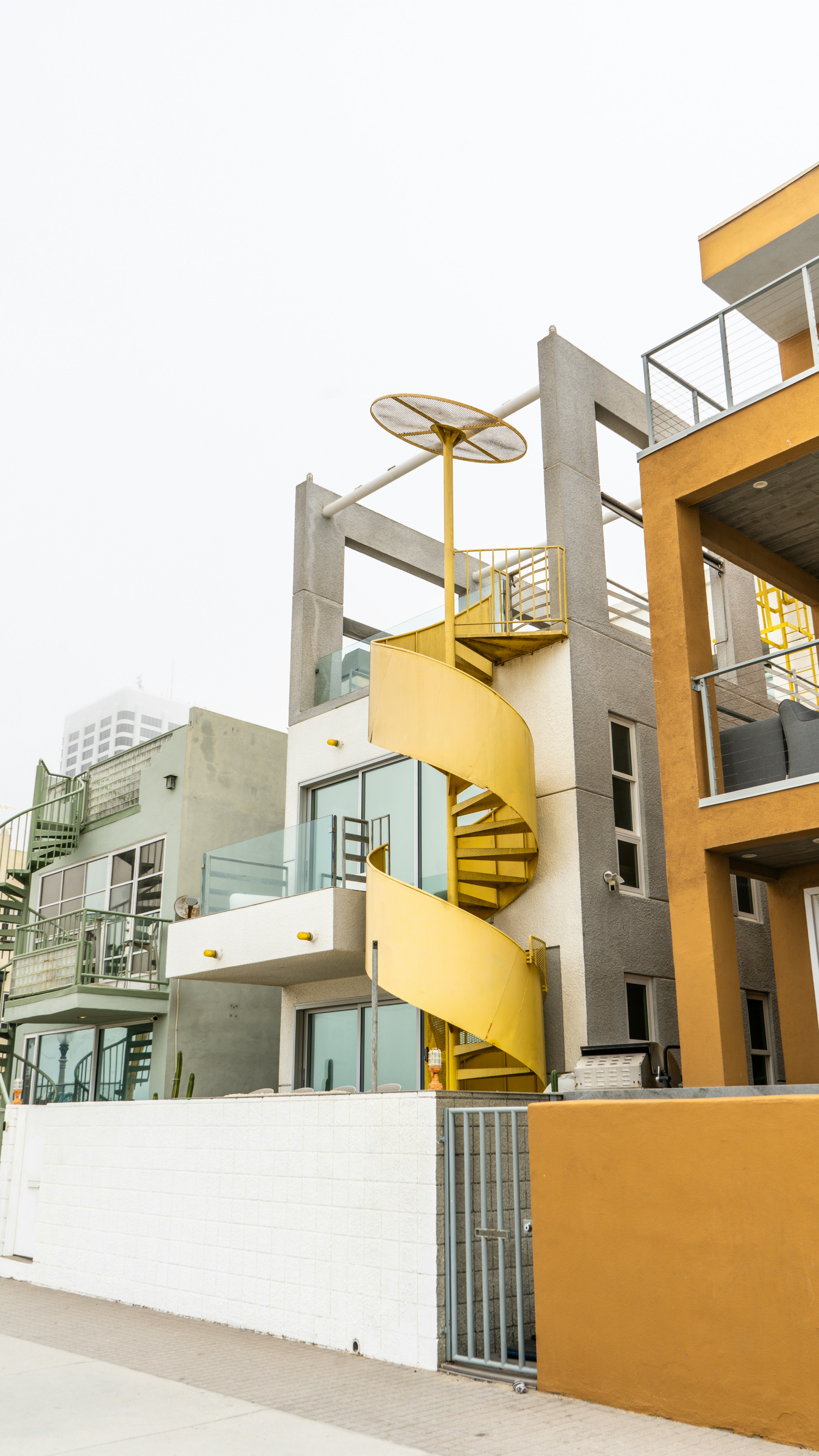 Architectural Helix: A Sunlit Yellow Spiral Staircase among Modern Facades