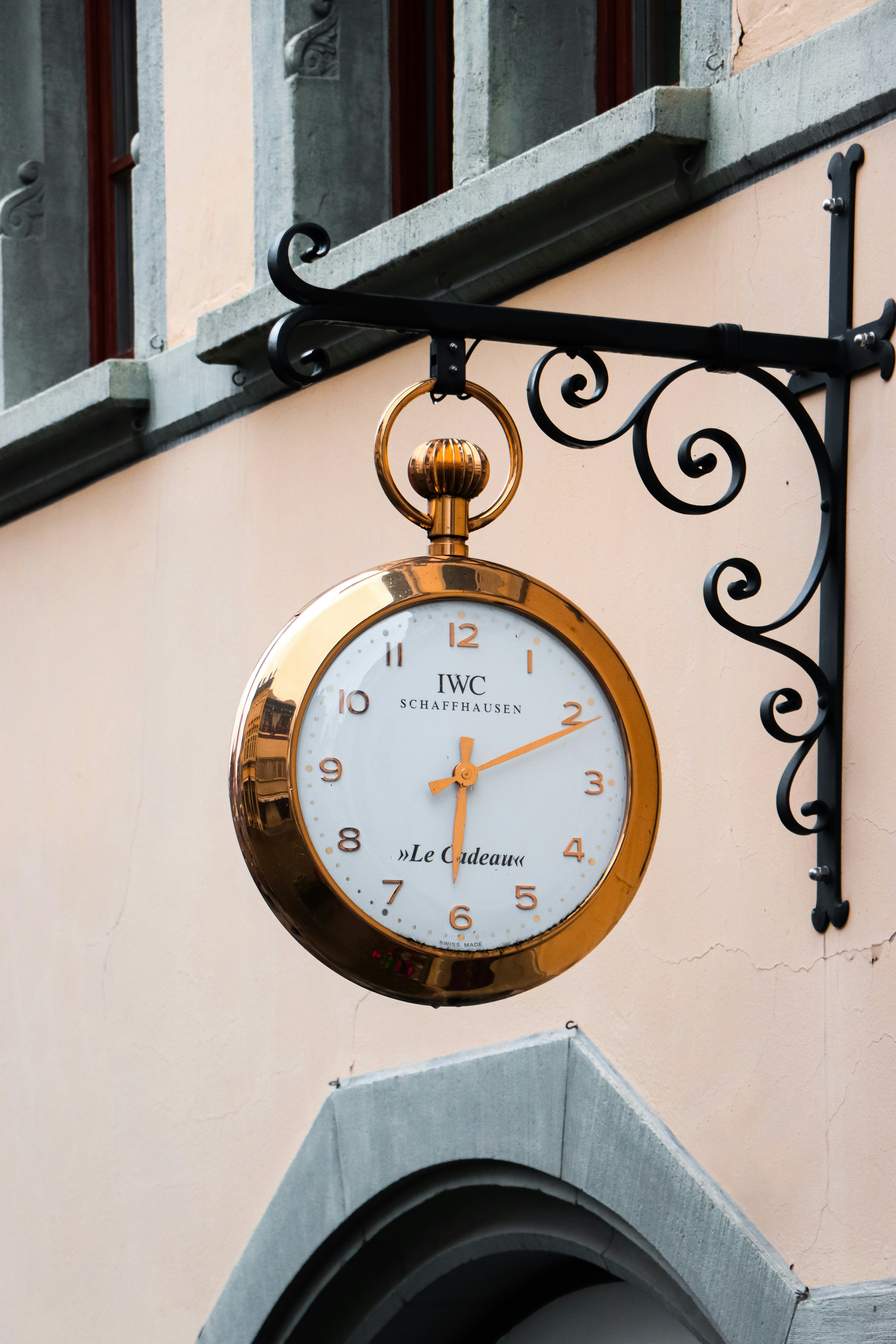 A clock hanging from the side of a building photo – Free City Image on ...