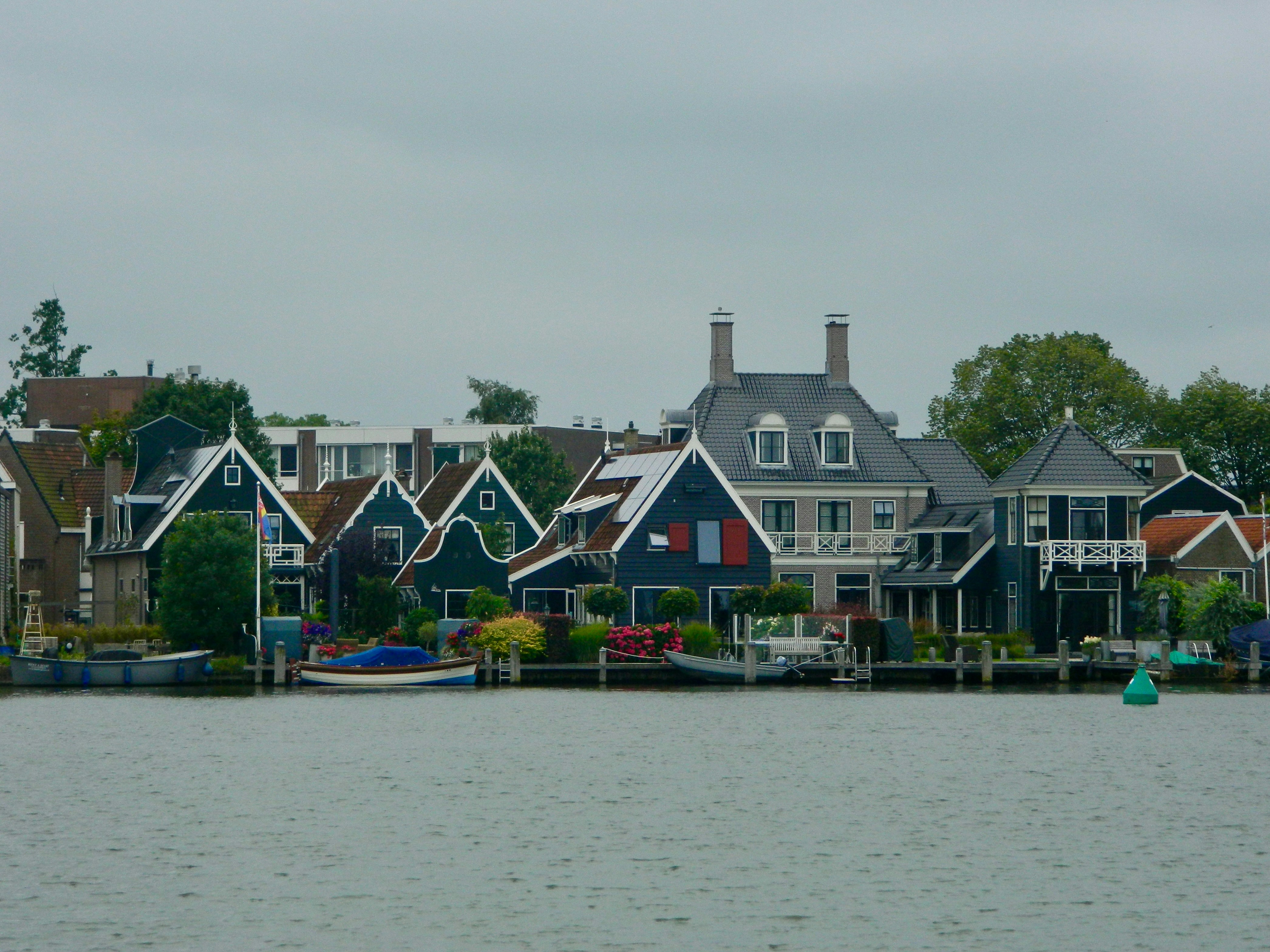 Colorful houses lining a serene waterfront, showcasing traditional Dutch architectural styles with boats moored nearby.
