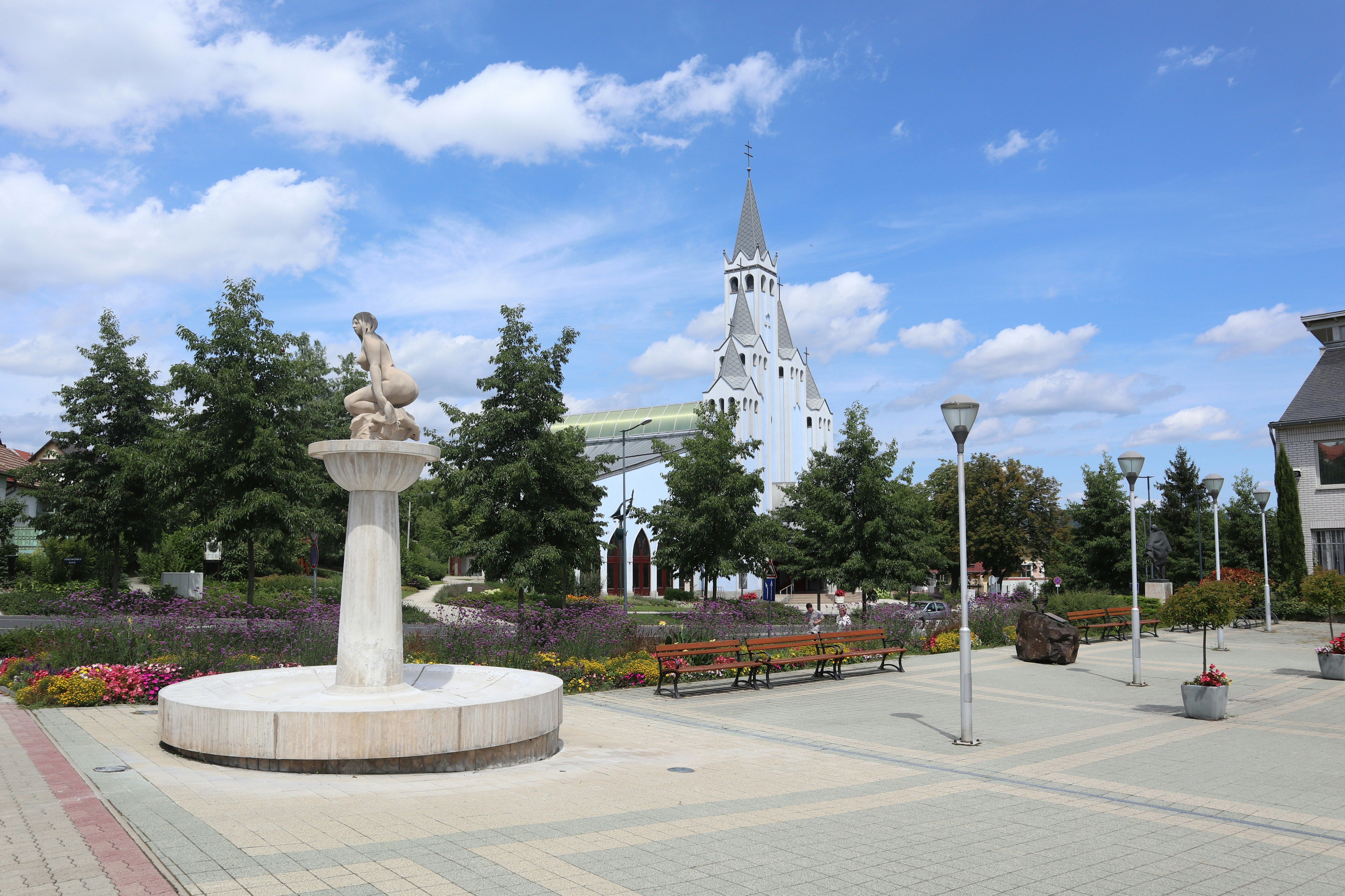Sunlit Plaza Portrait: Marble Fountain in Foreground with a White-Spired Church Rising Behind