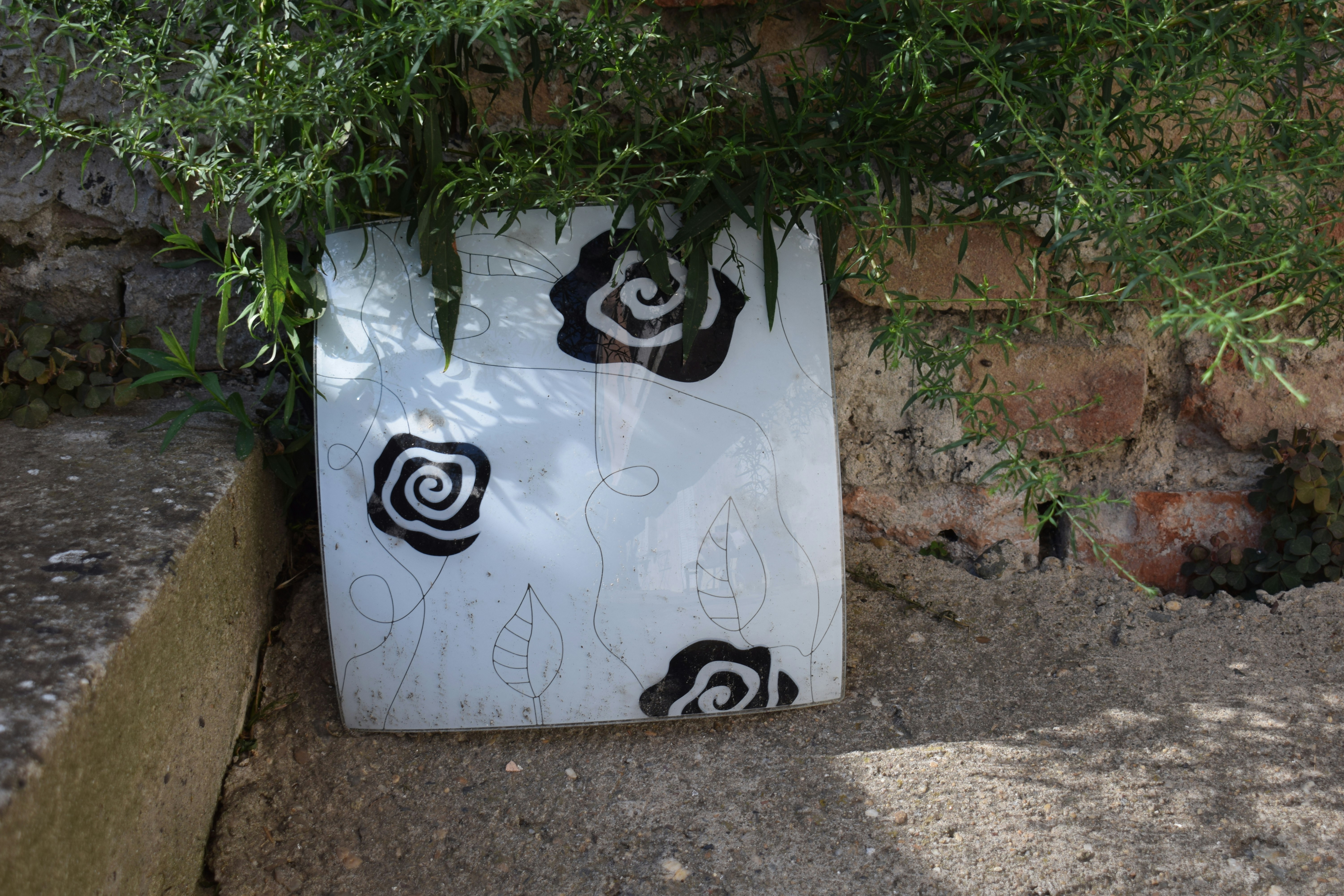 Shaded carton of decorative tiles tucked beside a brick wall