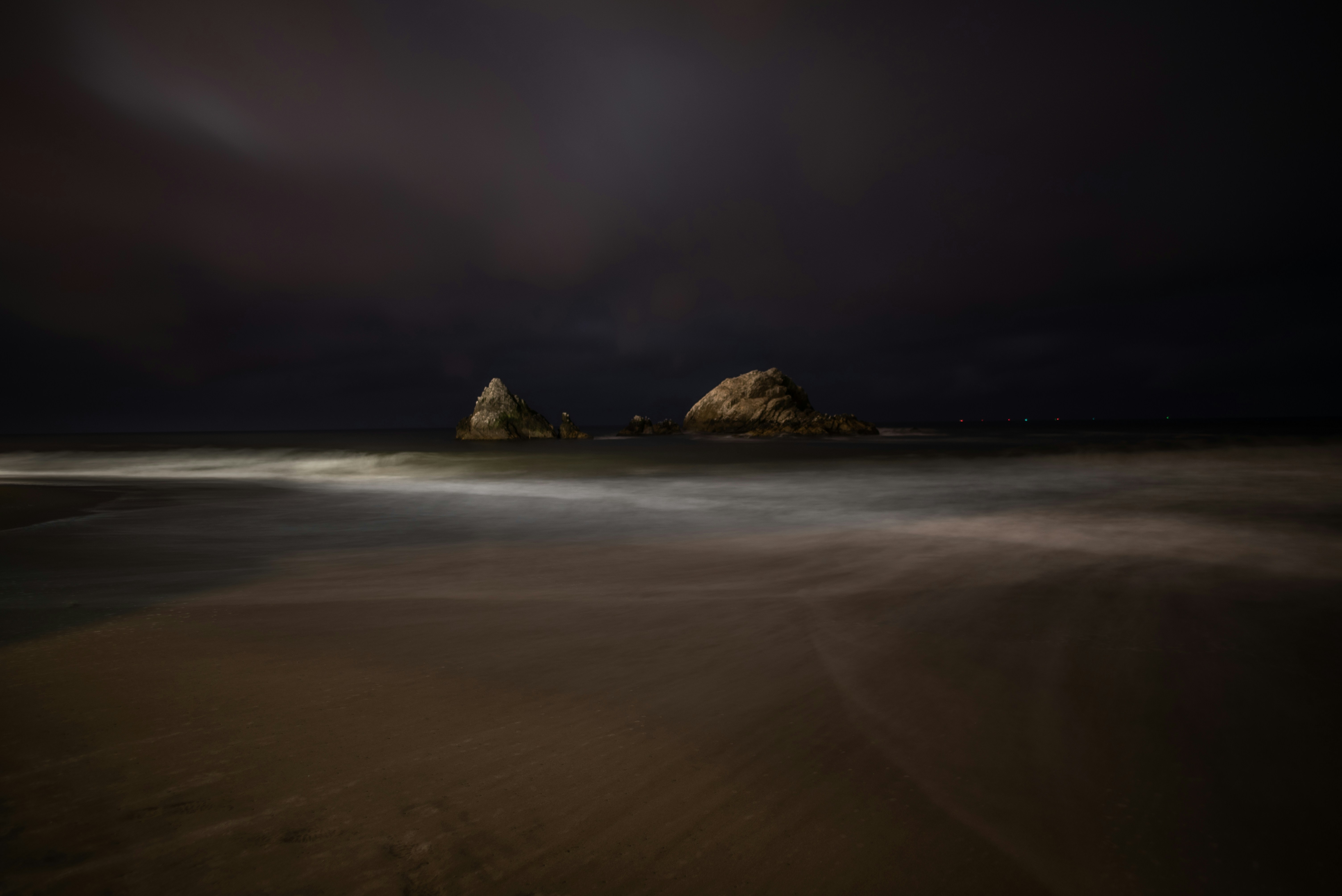 A night time picture of some rocks in the water photo – Free Beach ...