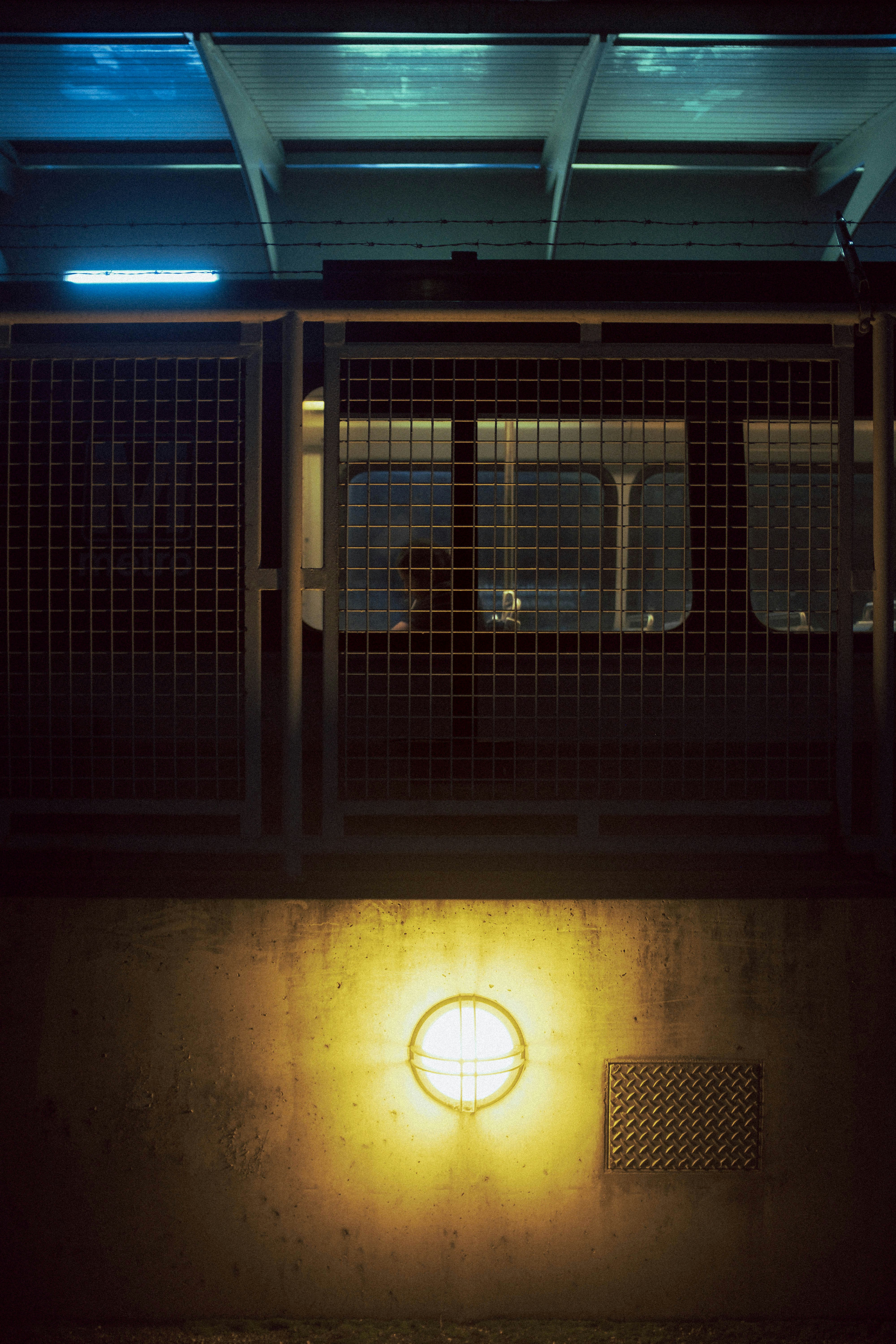 Gridded Twilight: A Train Behind Metal Fencing Meets a Warm Circular GlowIvan Mani