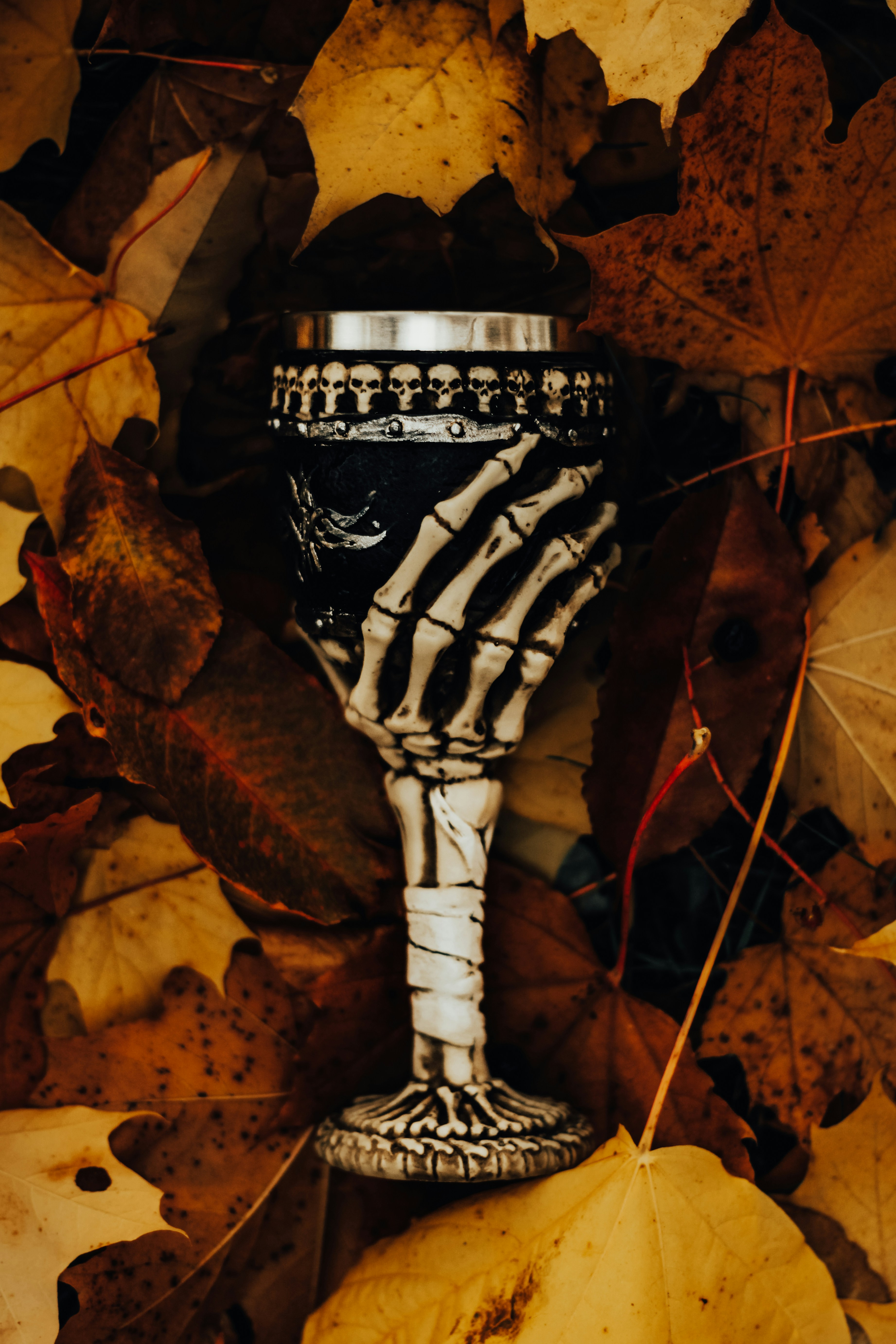 Autumn Reliquary: Skeleton Hand Grips a Skull-Goblet Amid Fallen Leaves