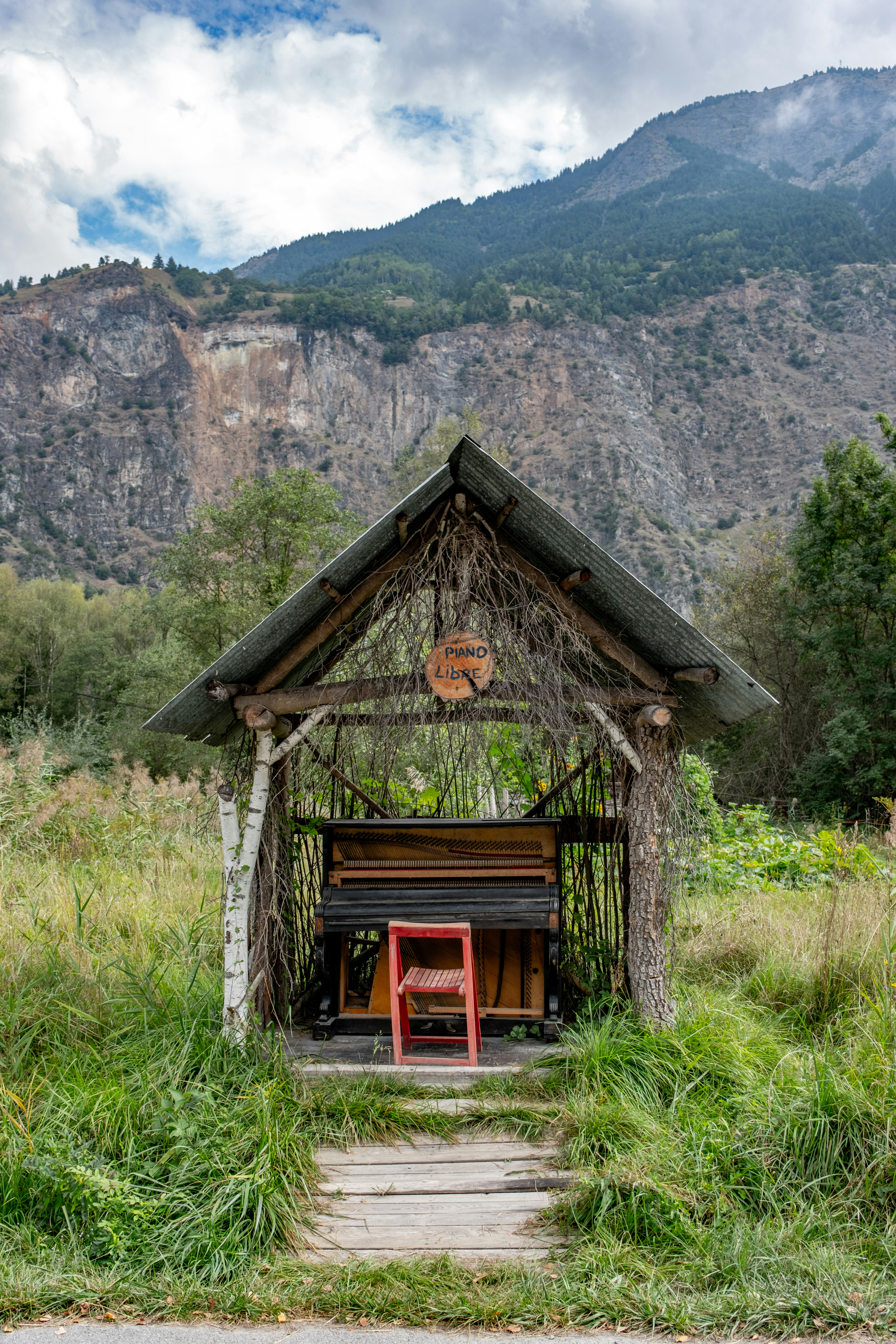 Piano in the Meadow: A Rustic Shelter Framing Music Against Mountain Backdrop