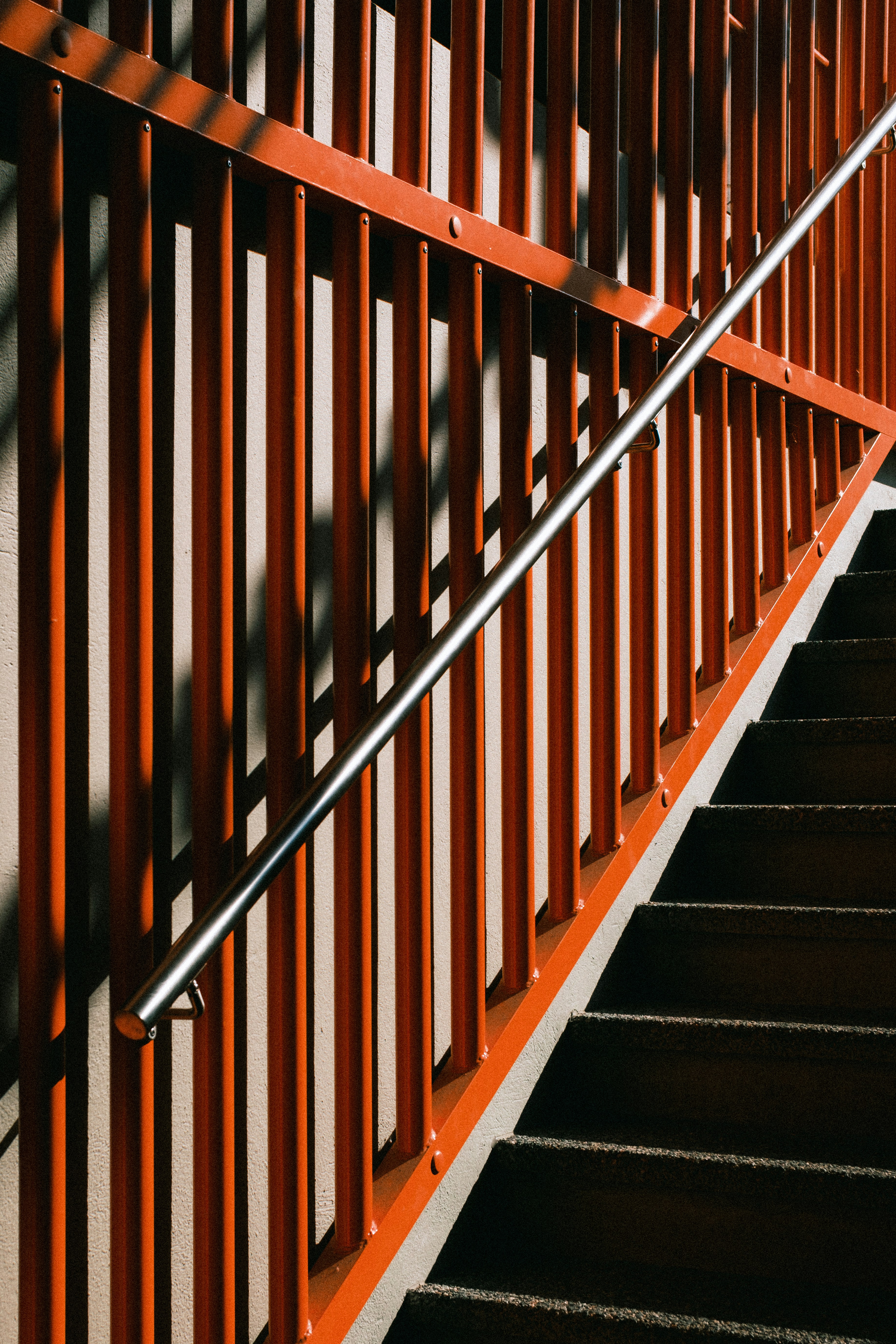 Crimson Rails Framing a Diagonal Staircase in Dim Light