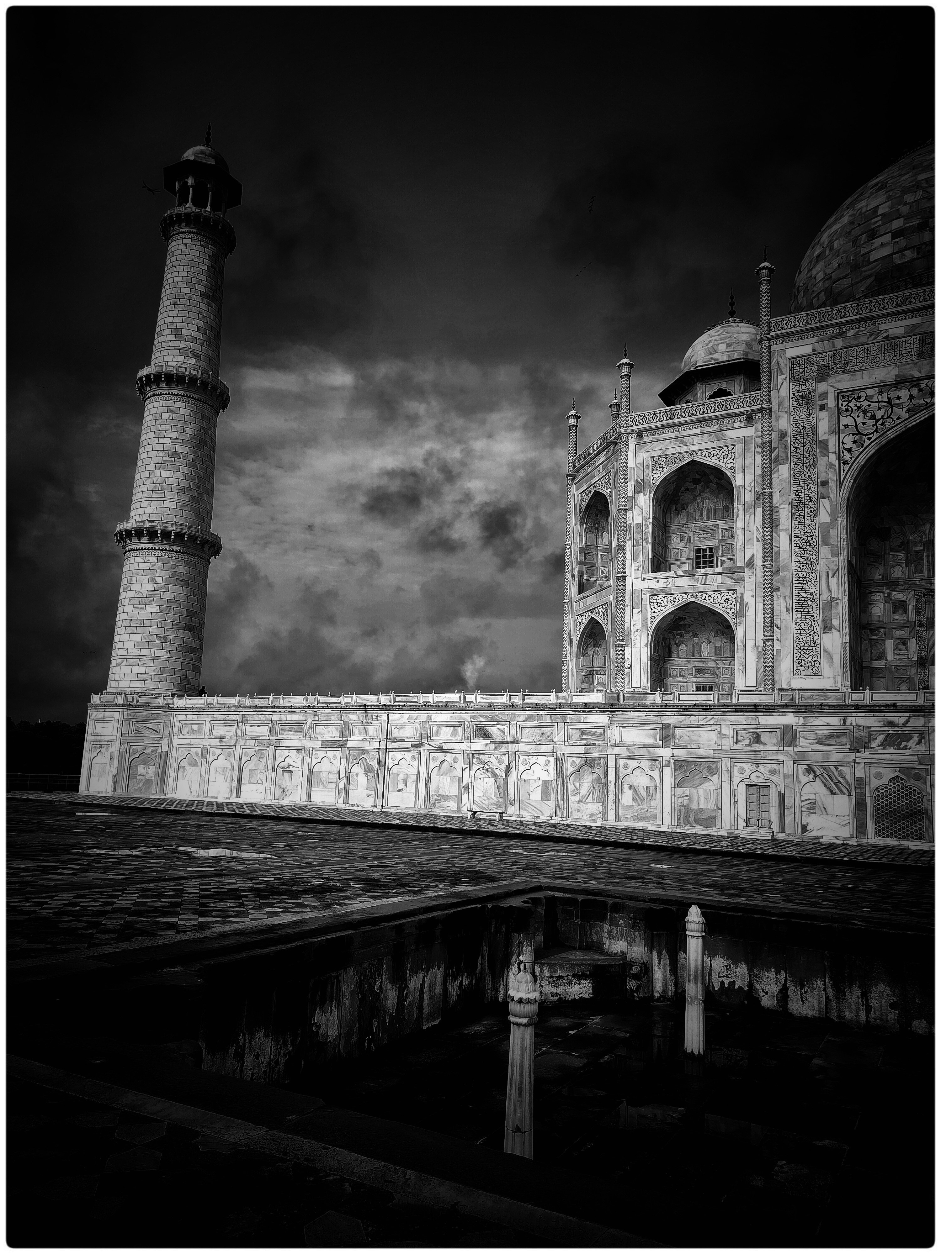 Intricate details of a historic mausoleum captured in monochrome, showcasing the grandeur of its architecture against a dramatic sky.