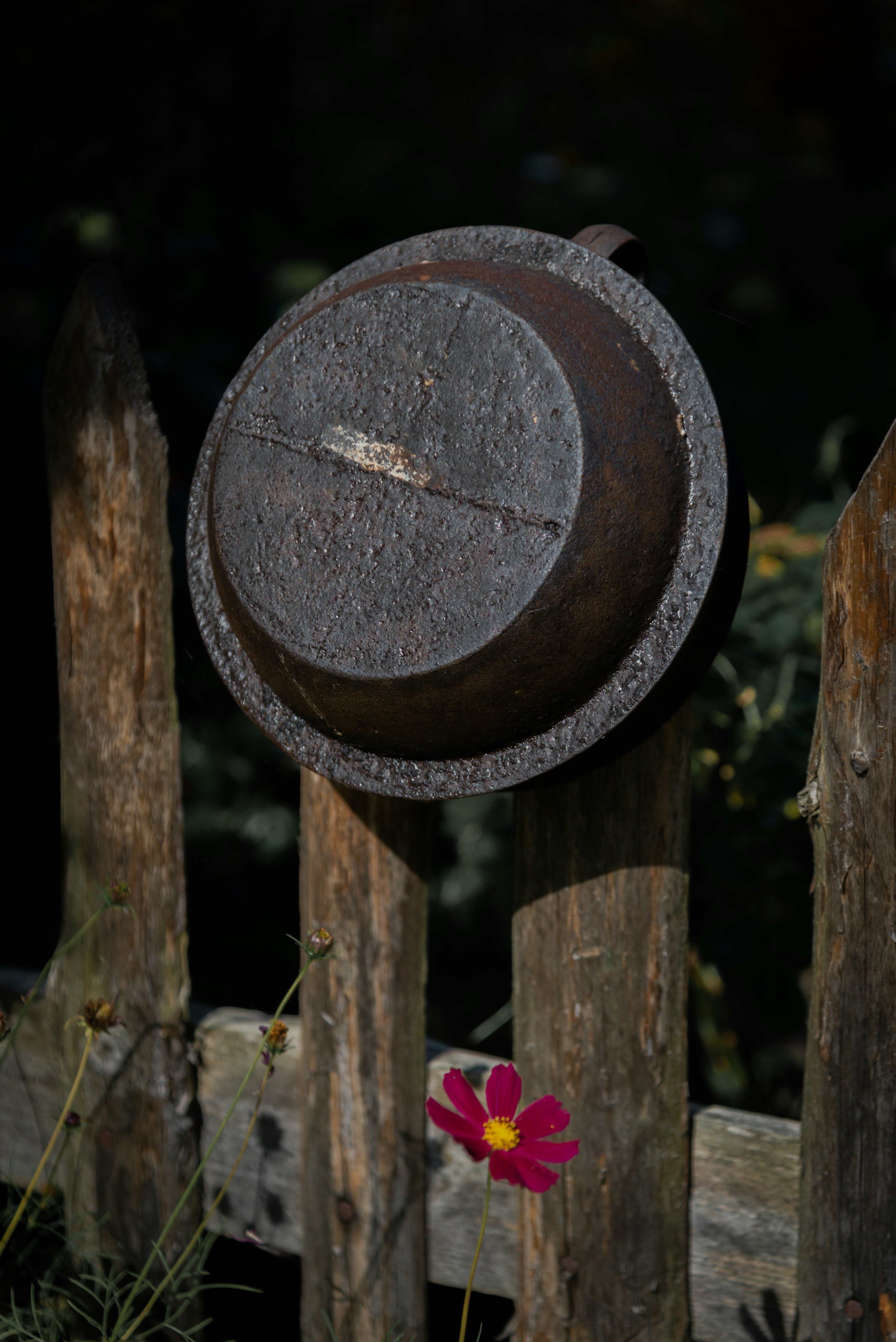 A rusted metal object sitting on top of a wooden fence