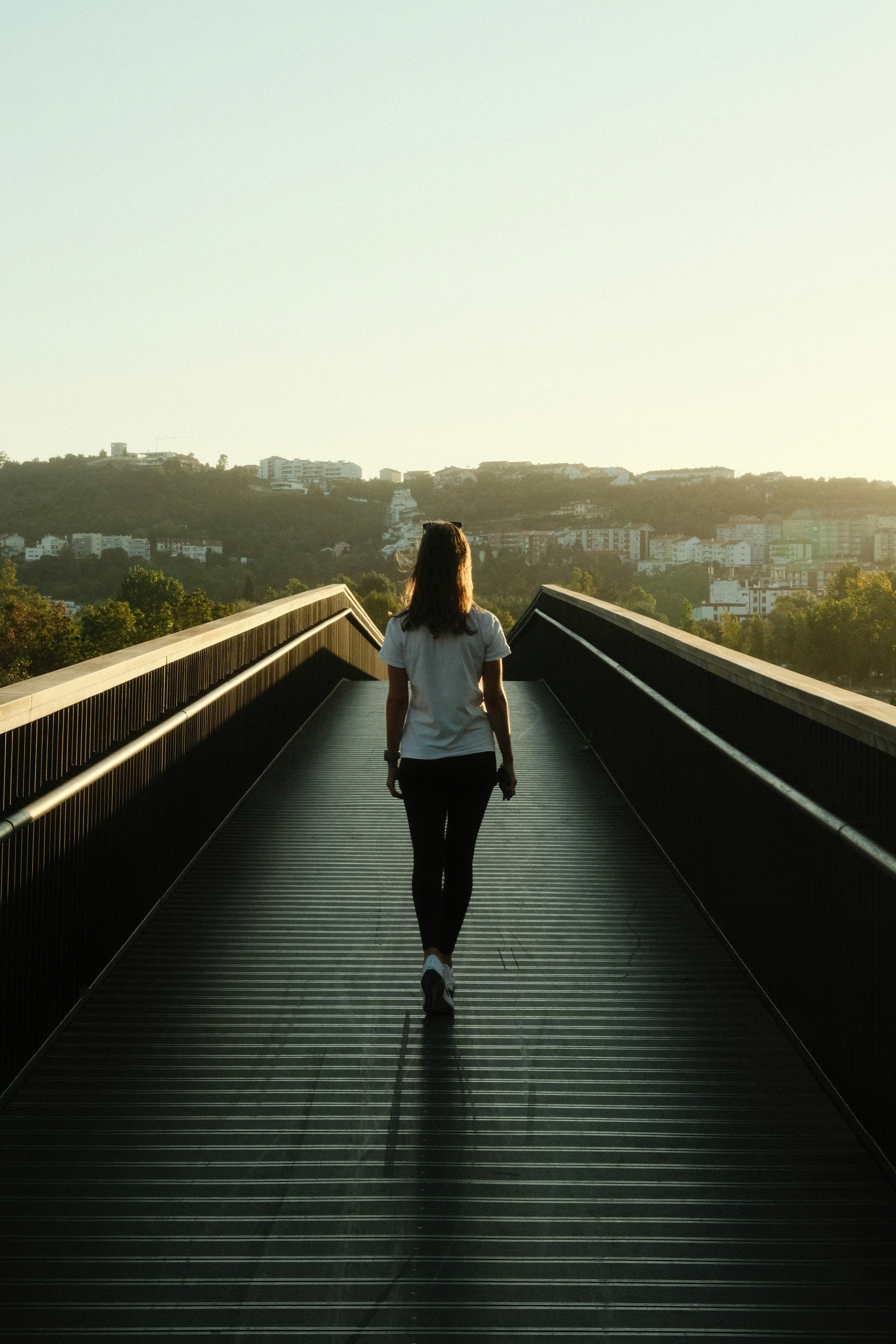 Golden Hour Crossing: A Lone Figure Traverses the Bridge Toward the City
