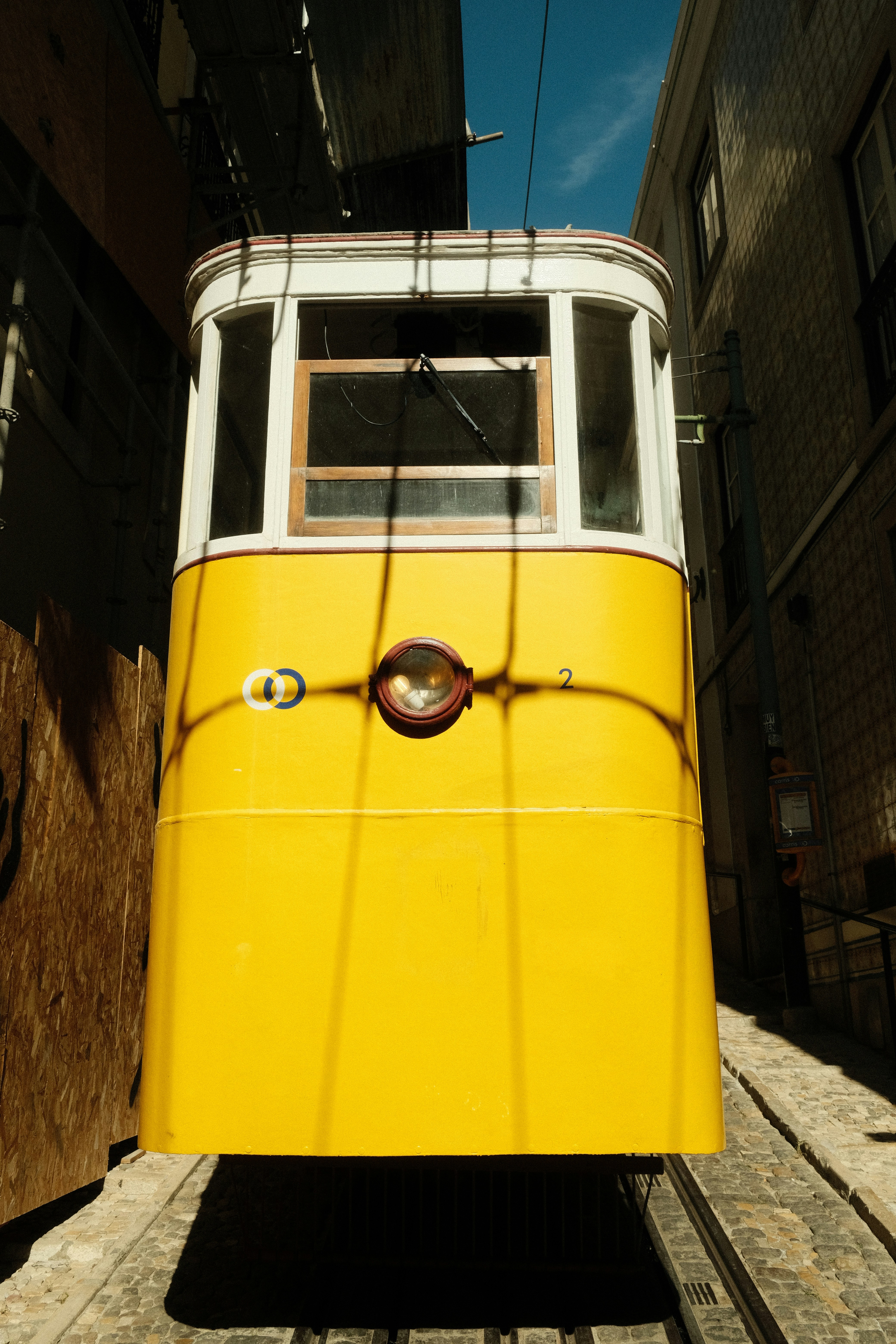 Sunlit Yellow Tram Framed by a Narrow Cobblestone Alley