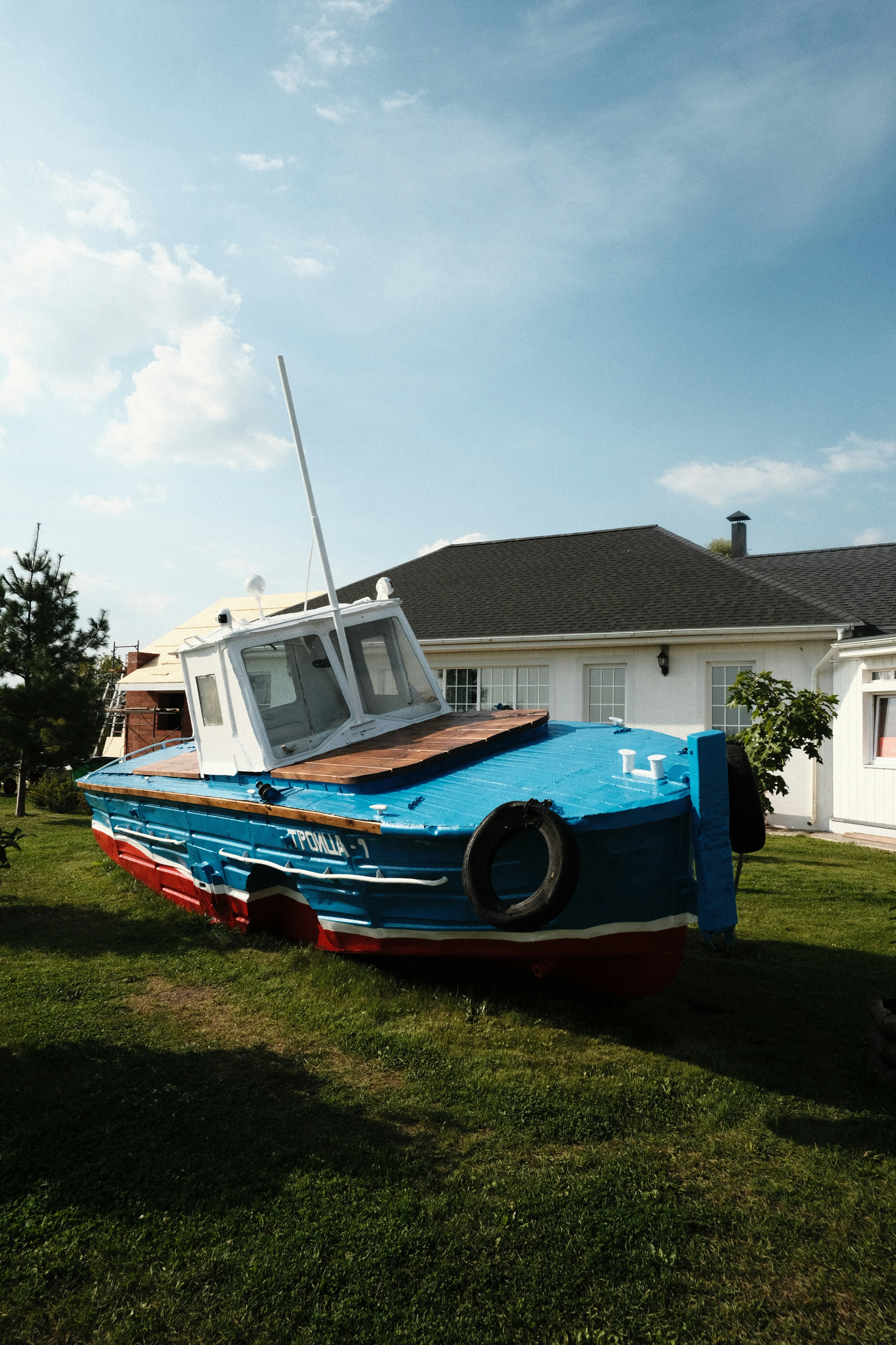 Beached Blue Boat Resting in a Sunlit Suburban Yard