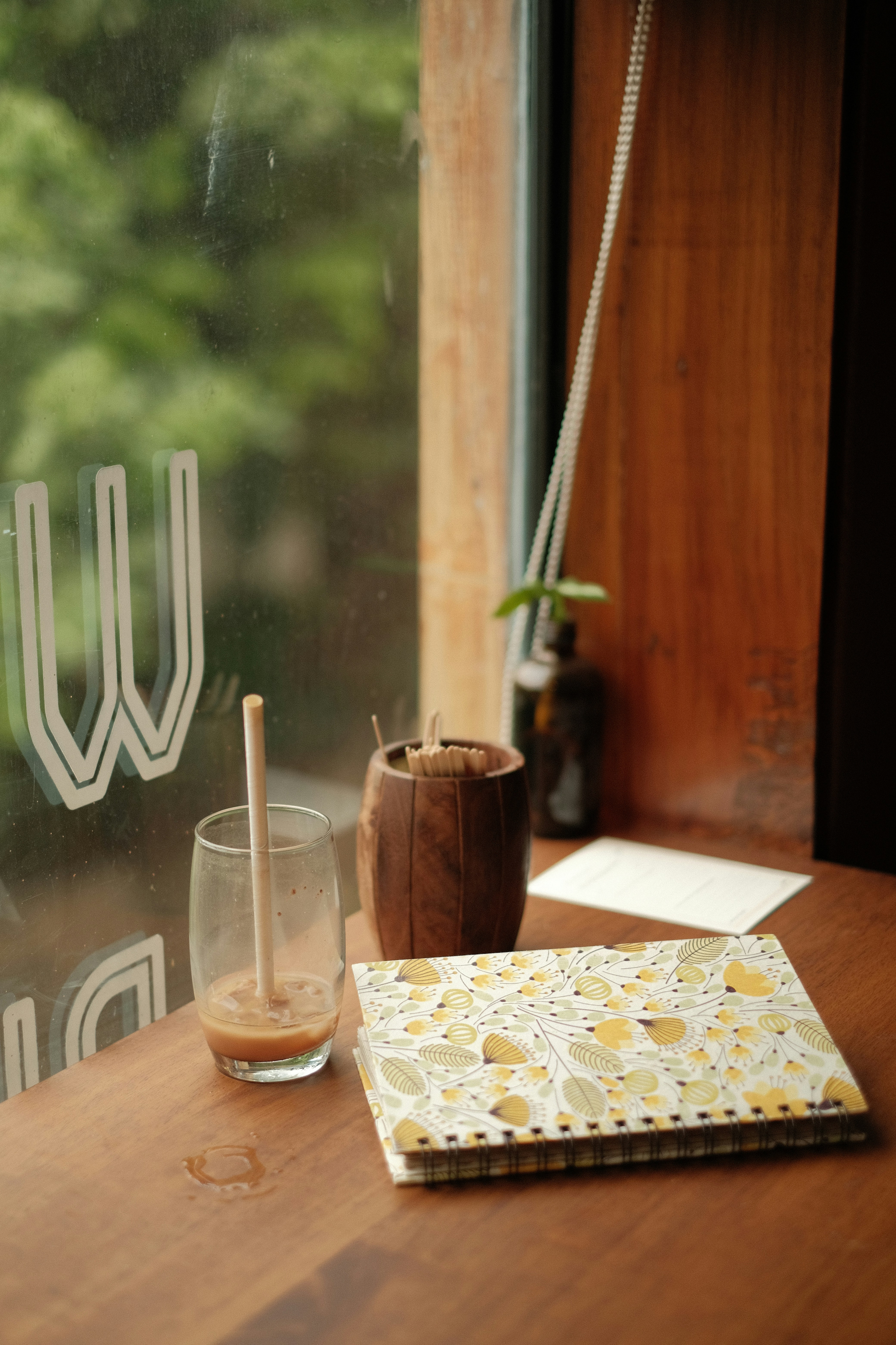 Leaf-Patterned Notebook by Window Light on a Cozy Café Table
