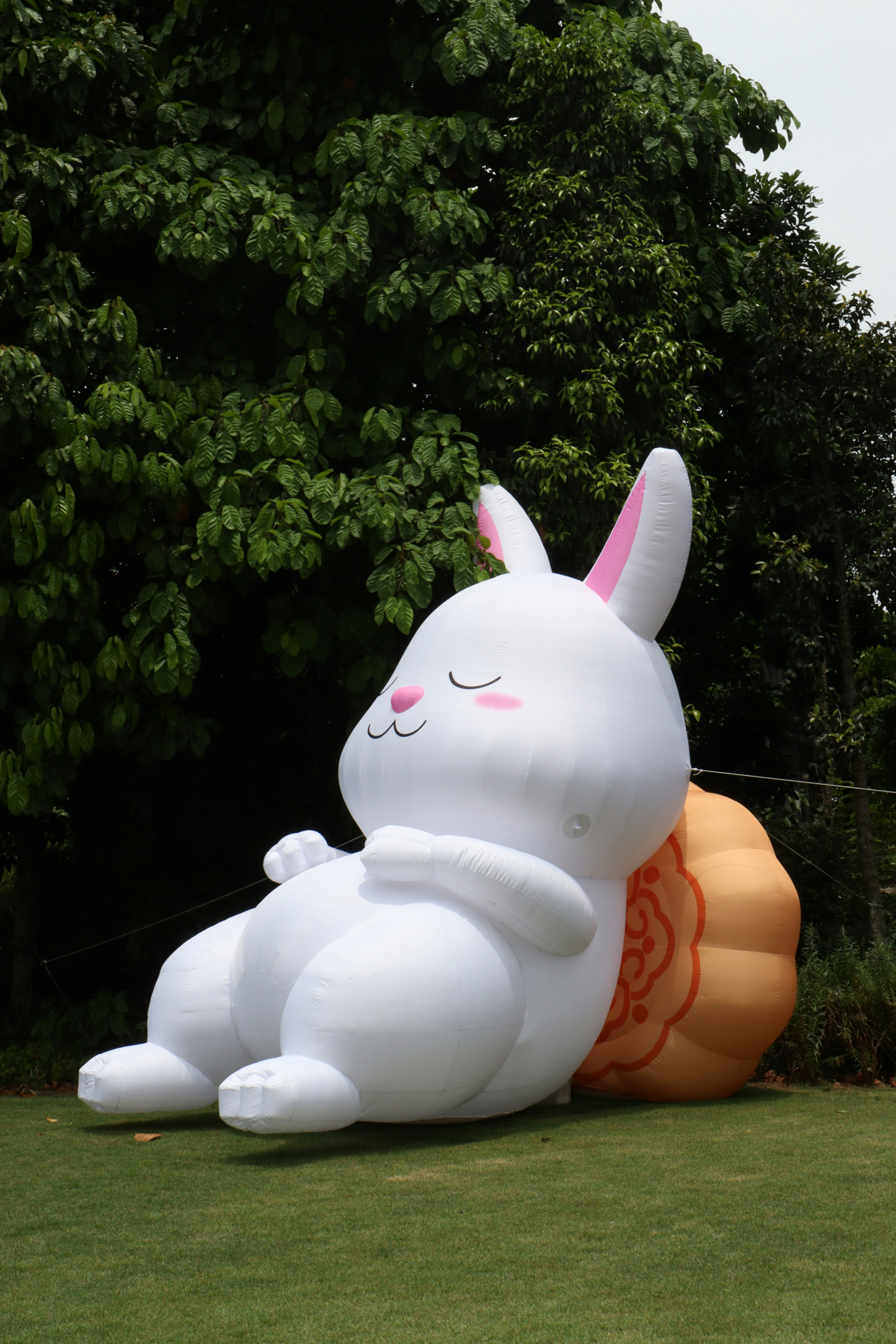 A large inflatable bunny sitting on top of a green field photo – Free ...