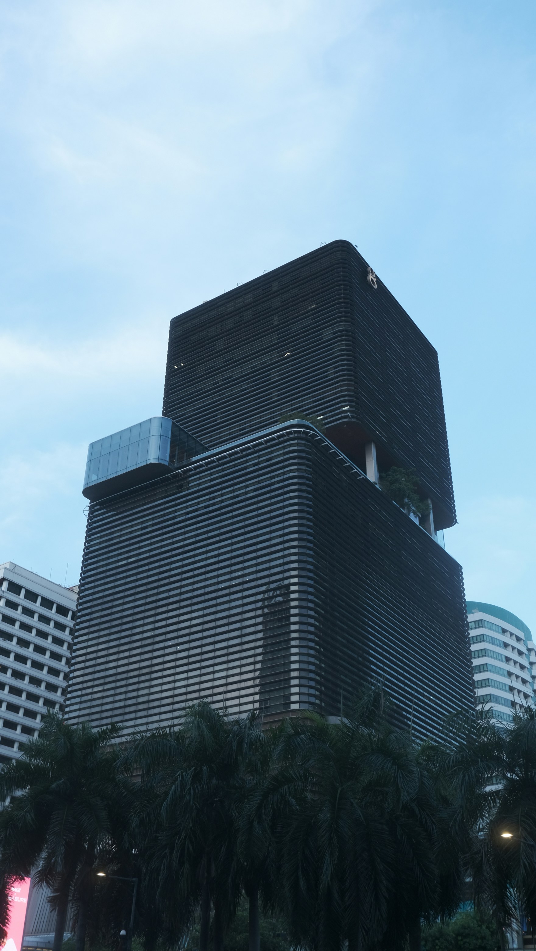 Tiered Black Louvered Tower Rising Over Palm-Front Silhouette
