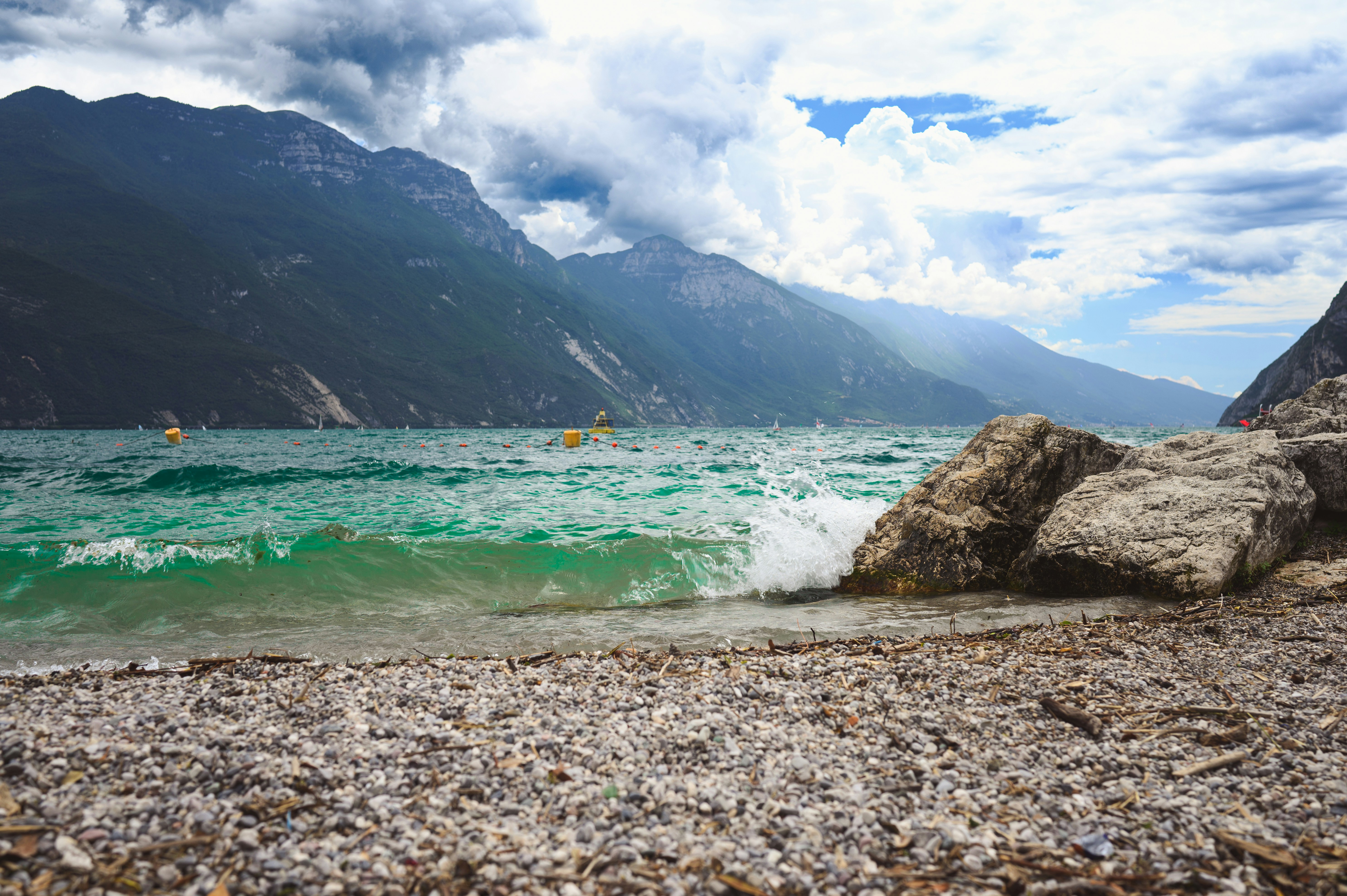 Rocky beach with turquoise waves crashing under a dramatic cloudy sky.