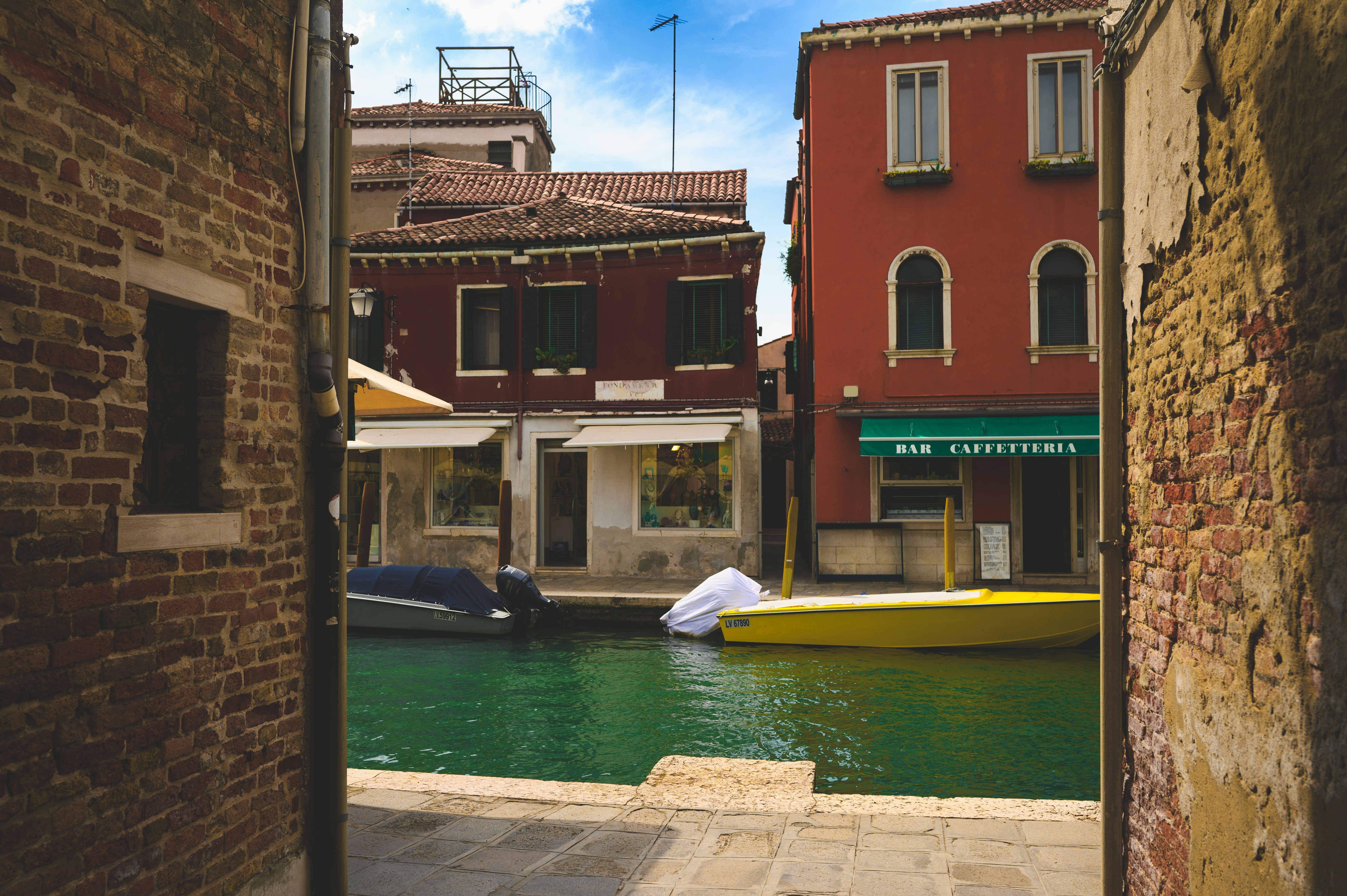 View of a tranquil canal lined with colorful buildings in bright daylight.