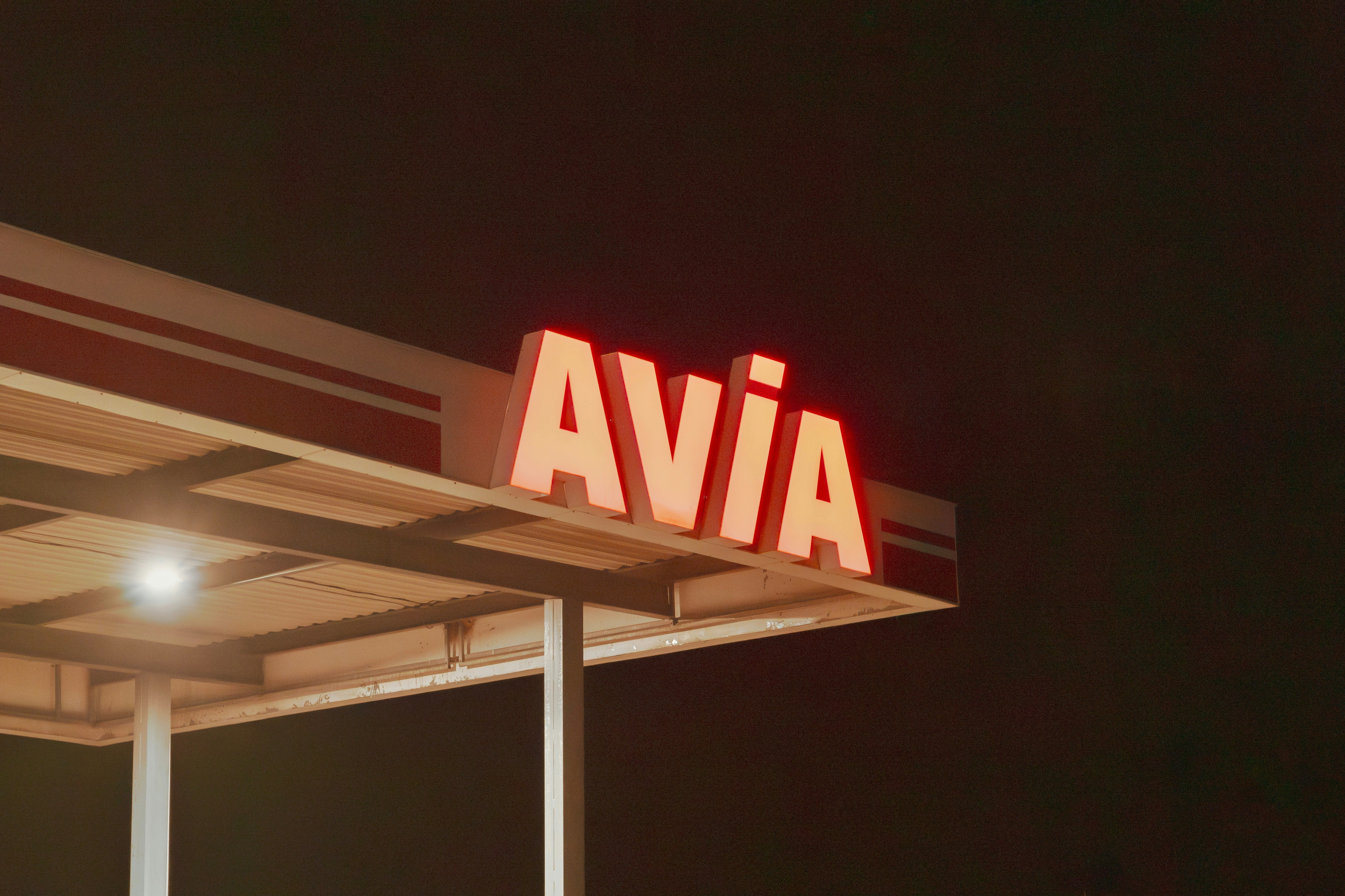 A gas station sign lit up at night photo – Free Machine Image on Unsplash