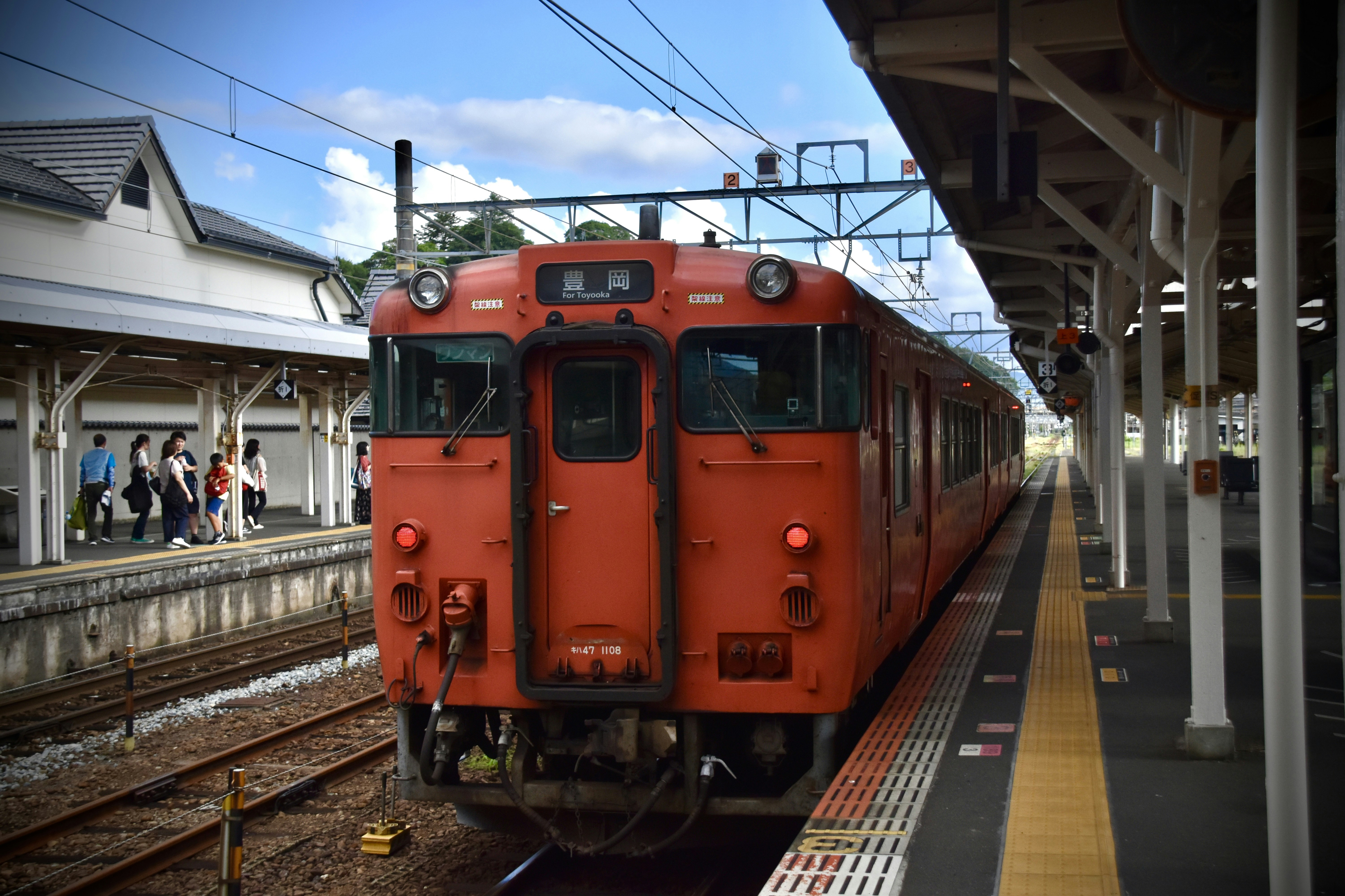 A red train pulling into a train station photo – Free Toyooka station ...