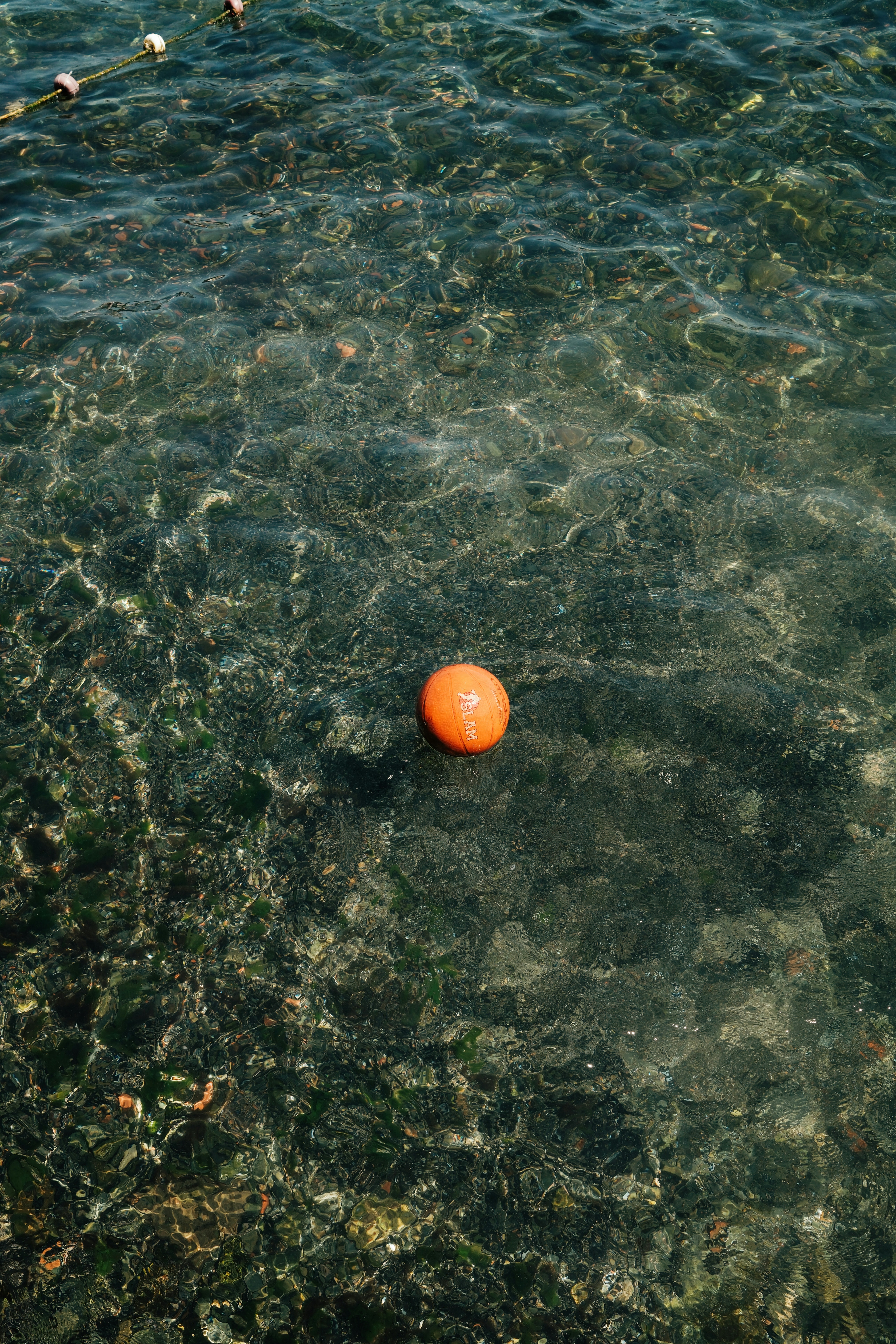 Lone Orange Buoy Drifting over Sunlit Shallows