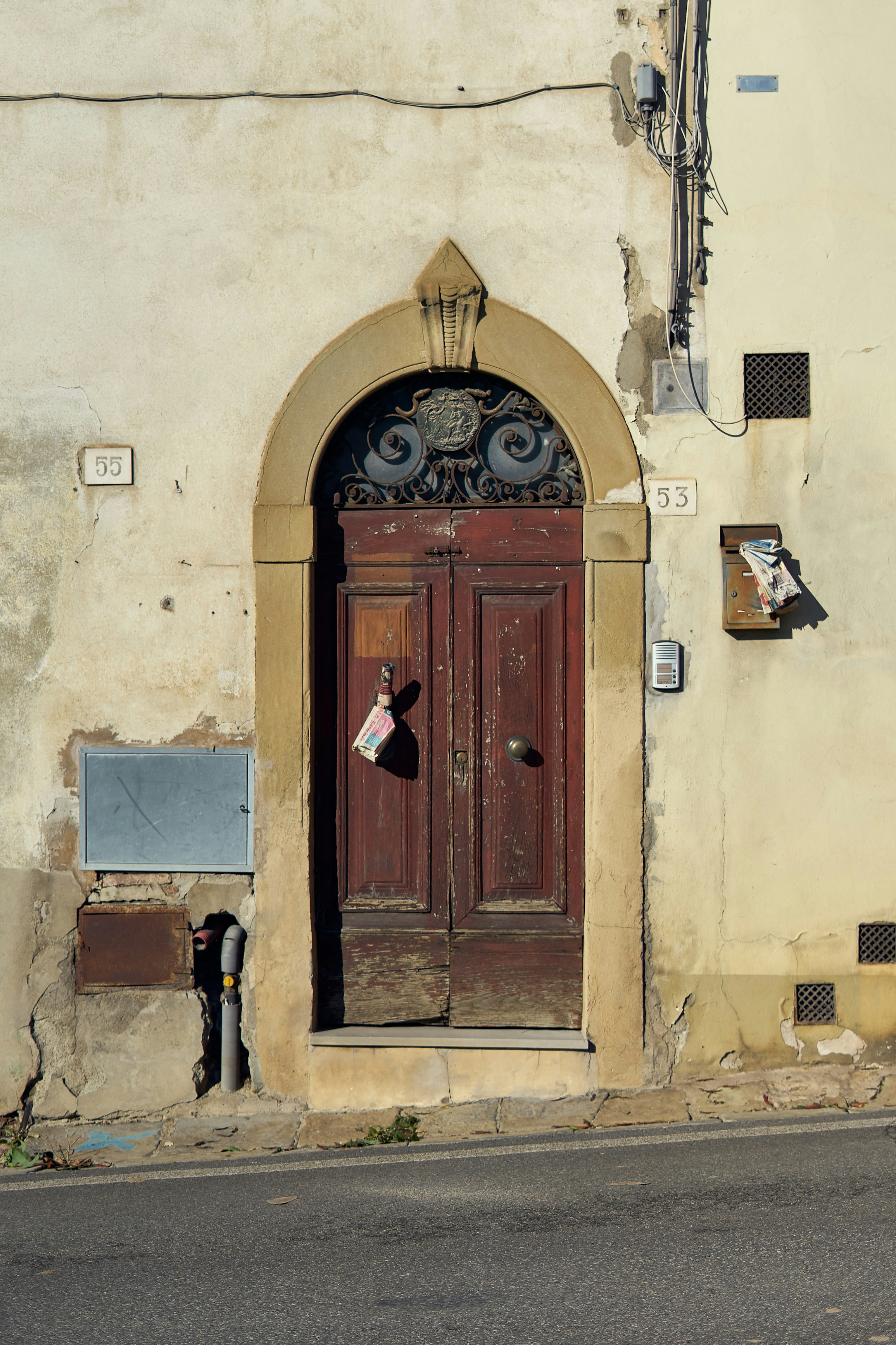 Threshold of Time: A Weathered Door Framed by a Creamy Arch in Dappled Sun