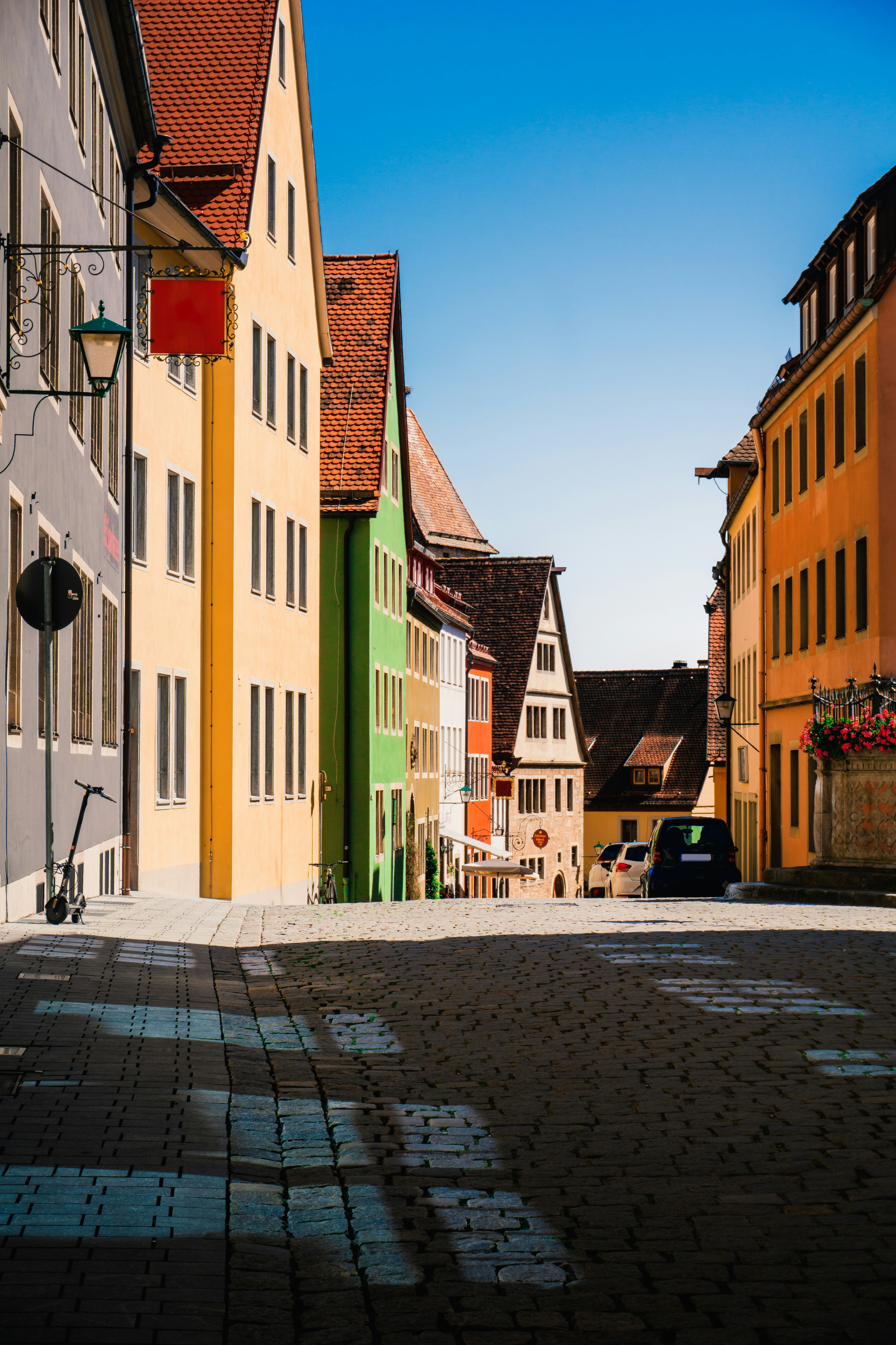 Pastel Lane Convergence: Sunlit Cobblestones and Colorful Facades