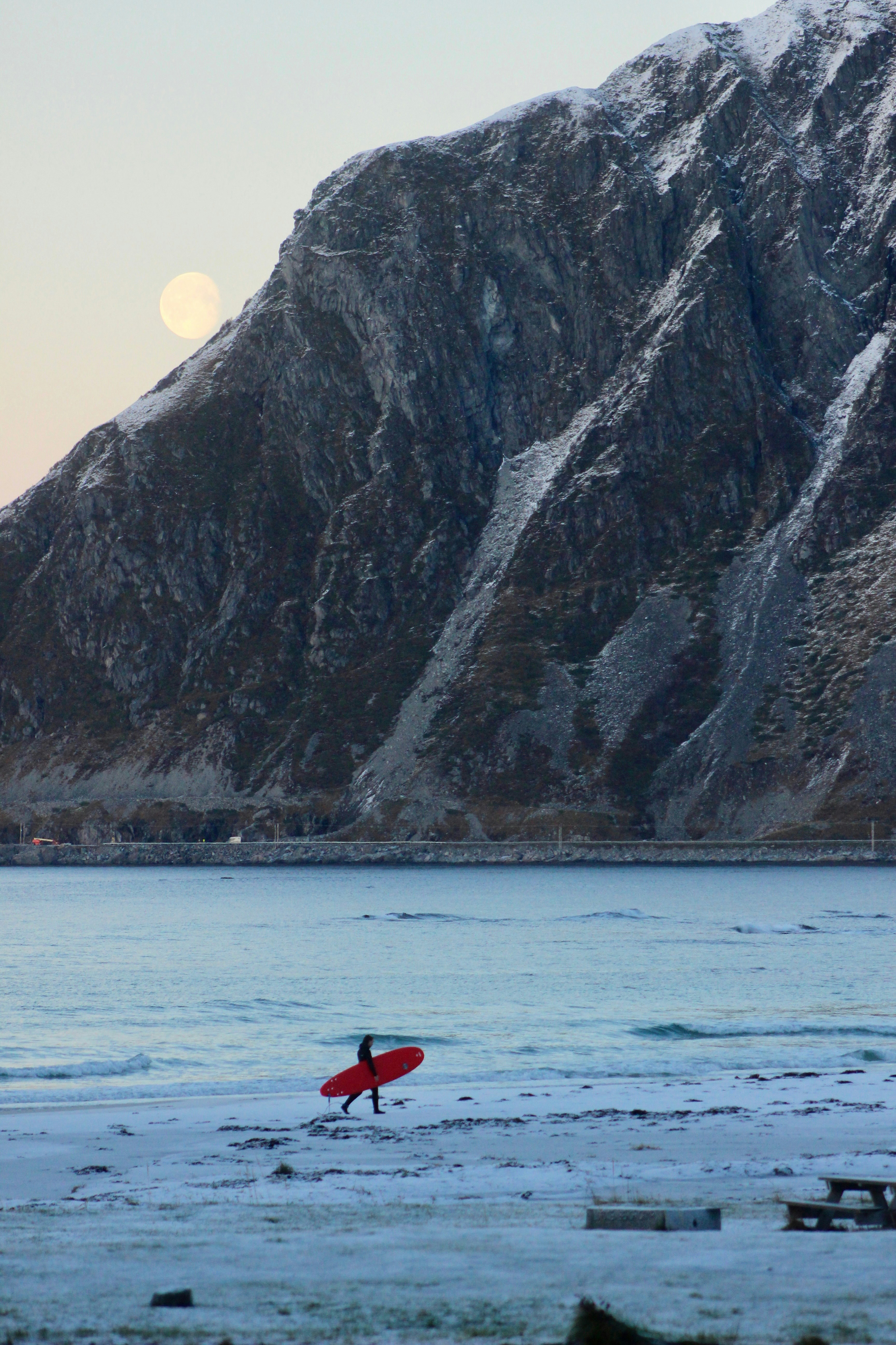 A person with a red surfboard in front of a mountain photo – Free ...
