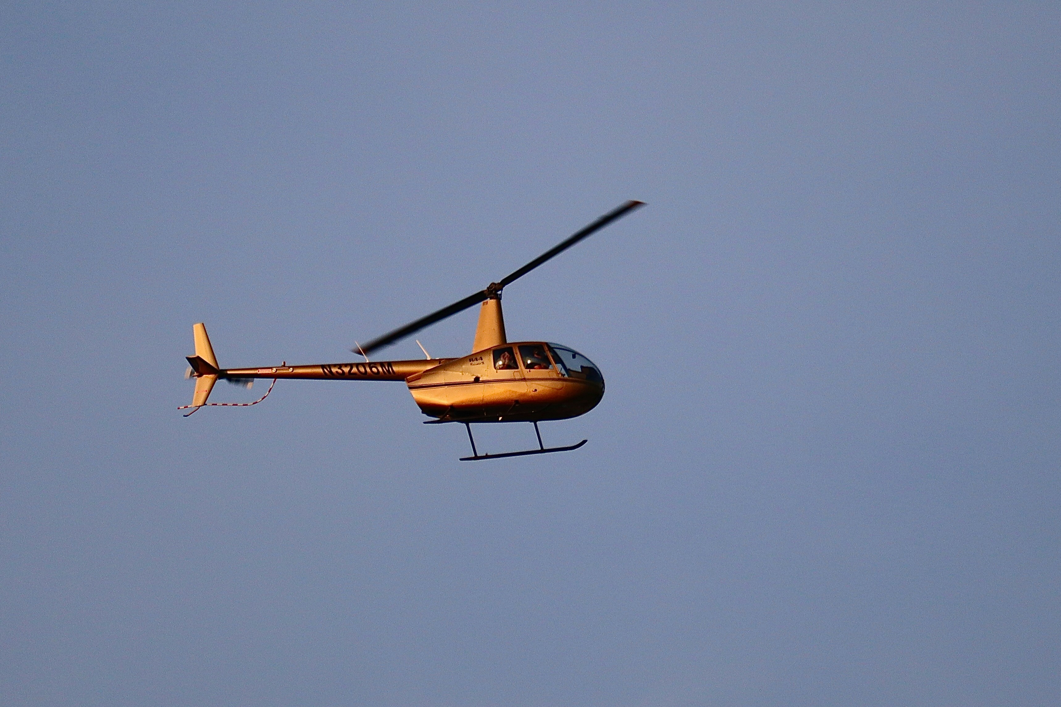 Golden helicopter tracing a quiet arc across a cobalt sky