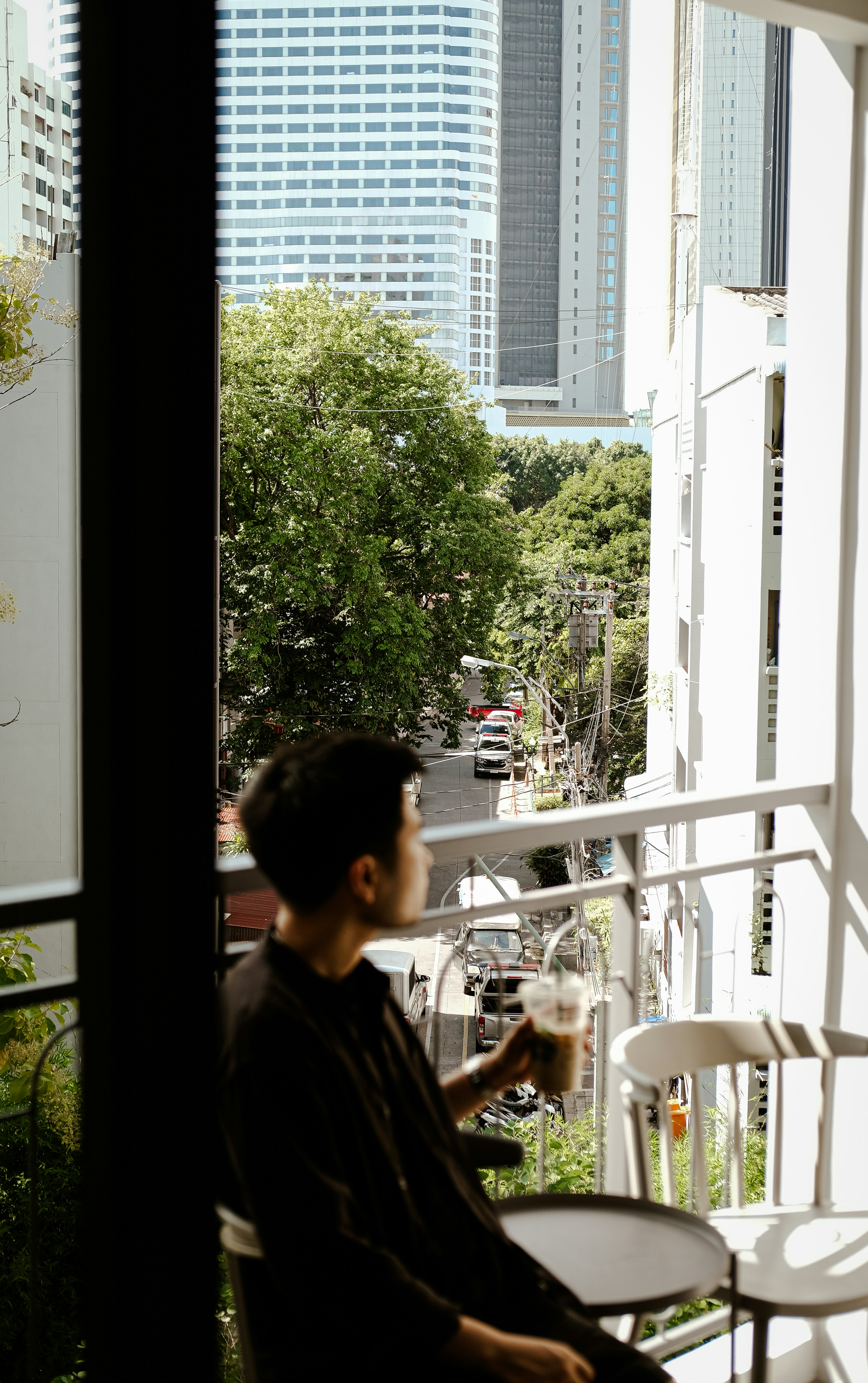 Espresso on the Edge: A Quiet Balcony Portrait Against a Glassy City