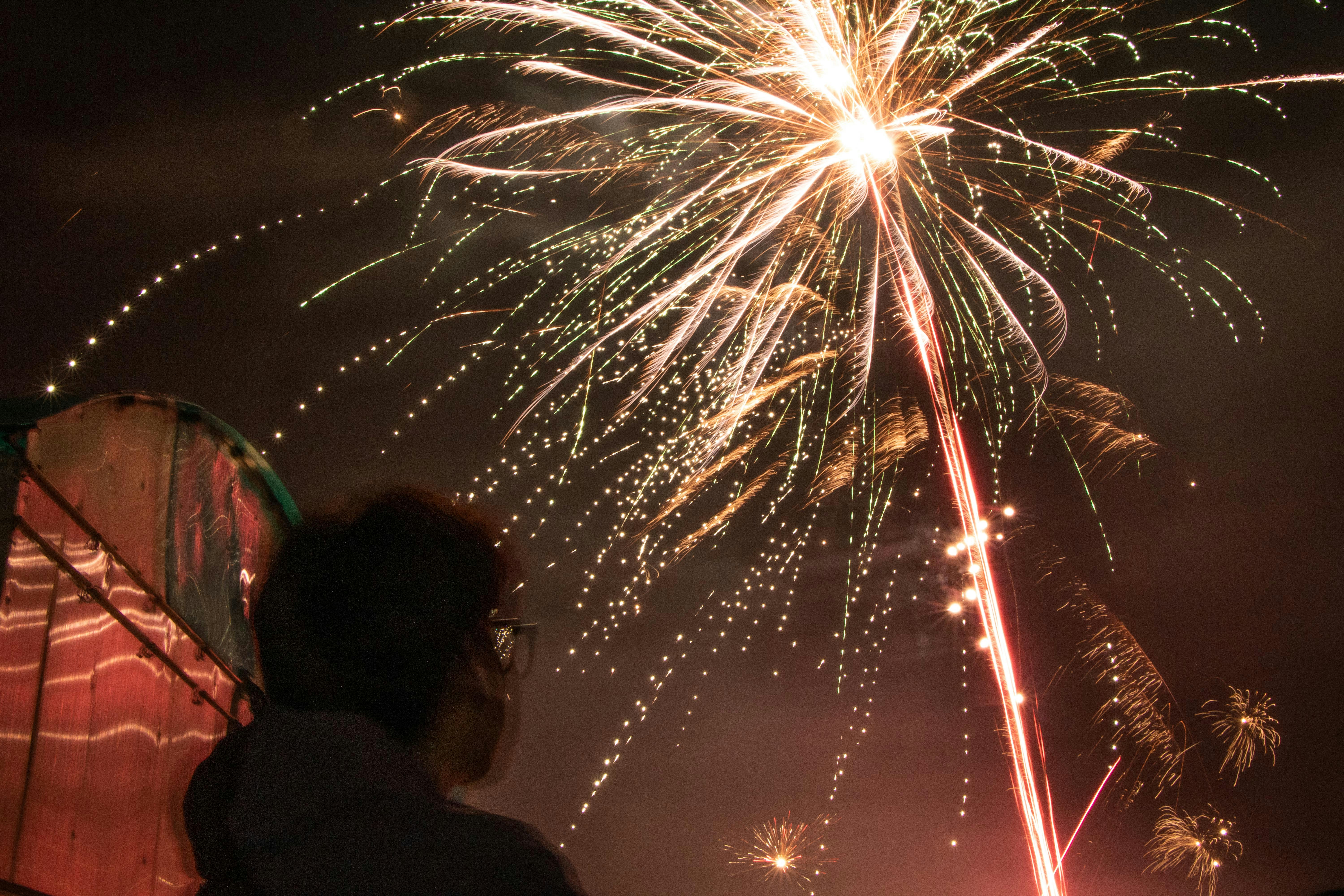 A man looking at a fireworks display in the night sky photo – Free ...