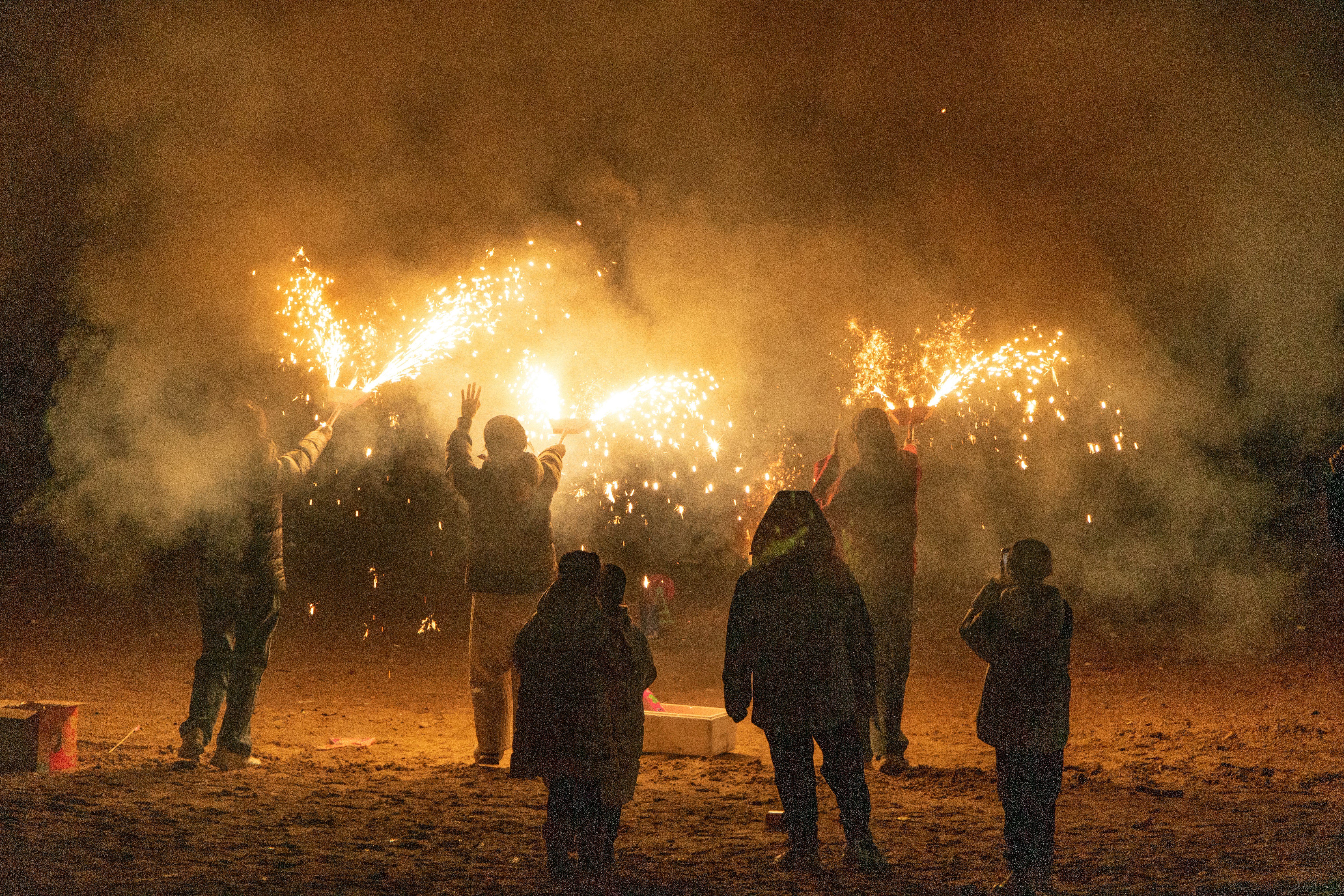 A group of people standing around a field with fireworks photo – Free ...