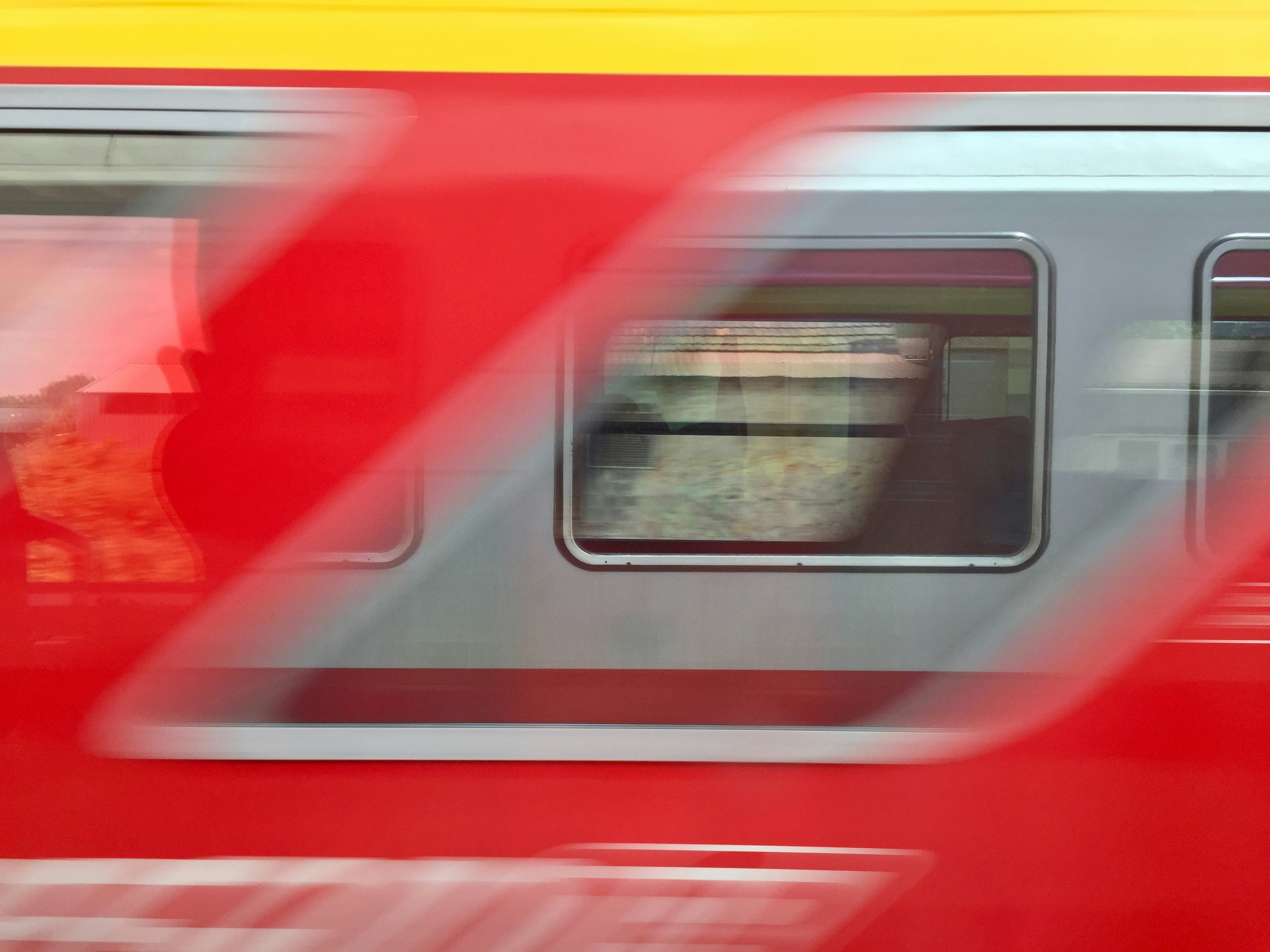 Blurred motion of a red and yellow train passing swiftly, capturing the essence of speed and energy.