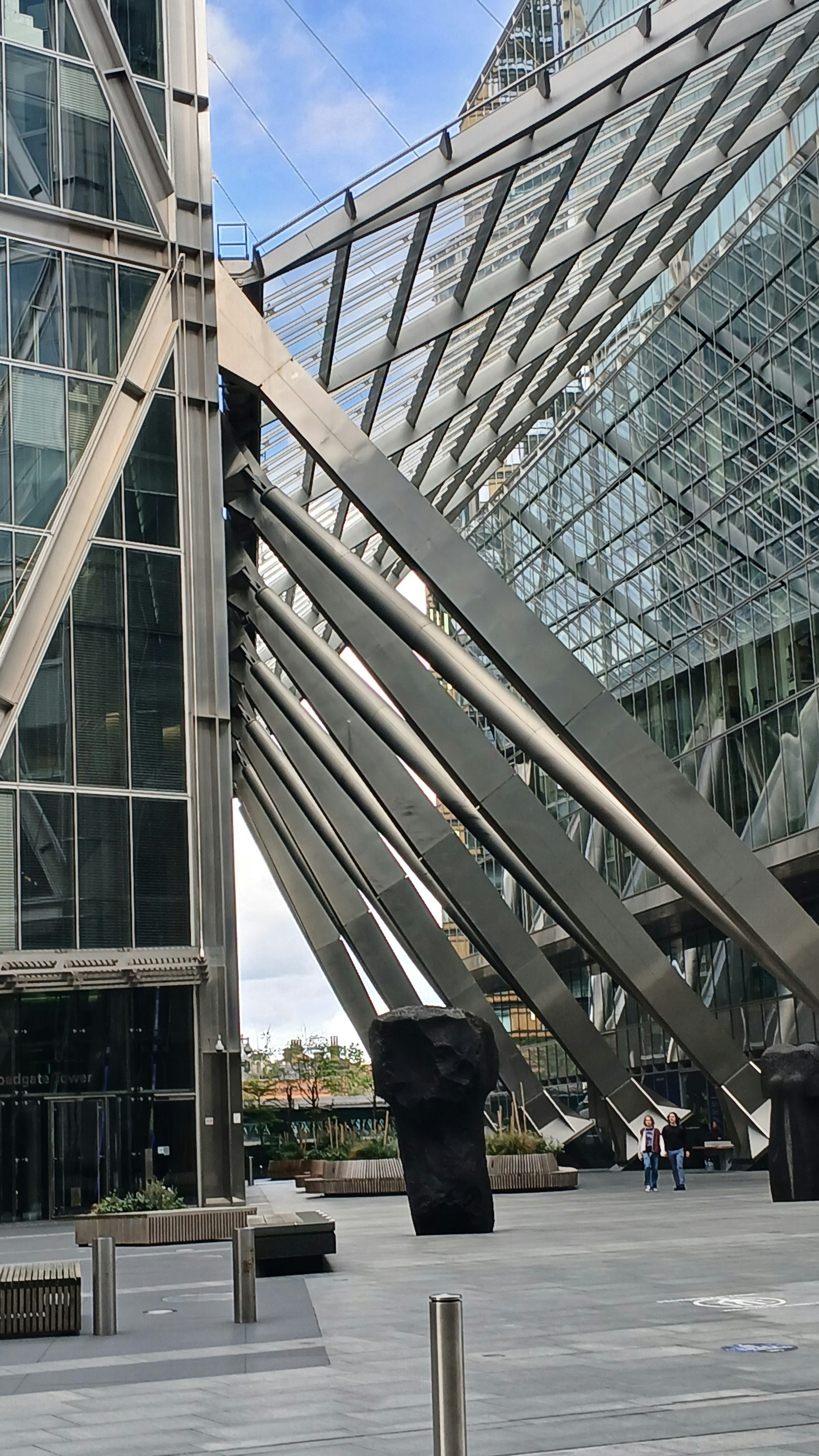 Latticed Giants: Diagonal Steel Frames Framing a Glass Plaza