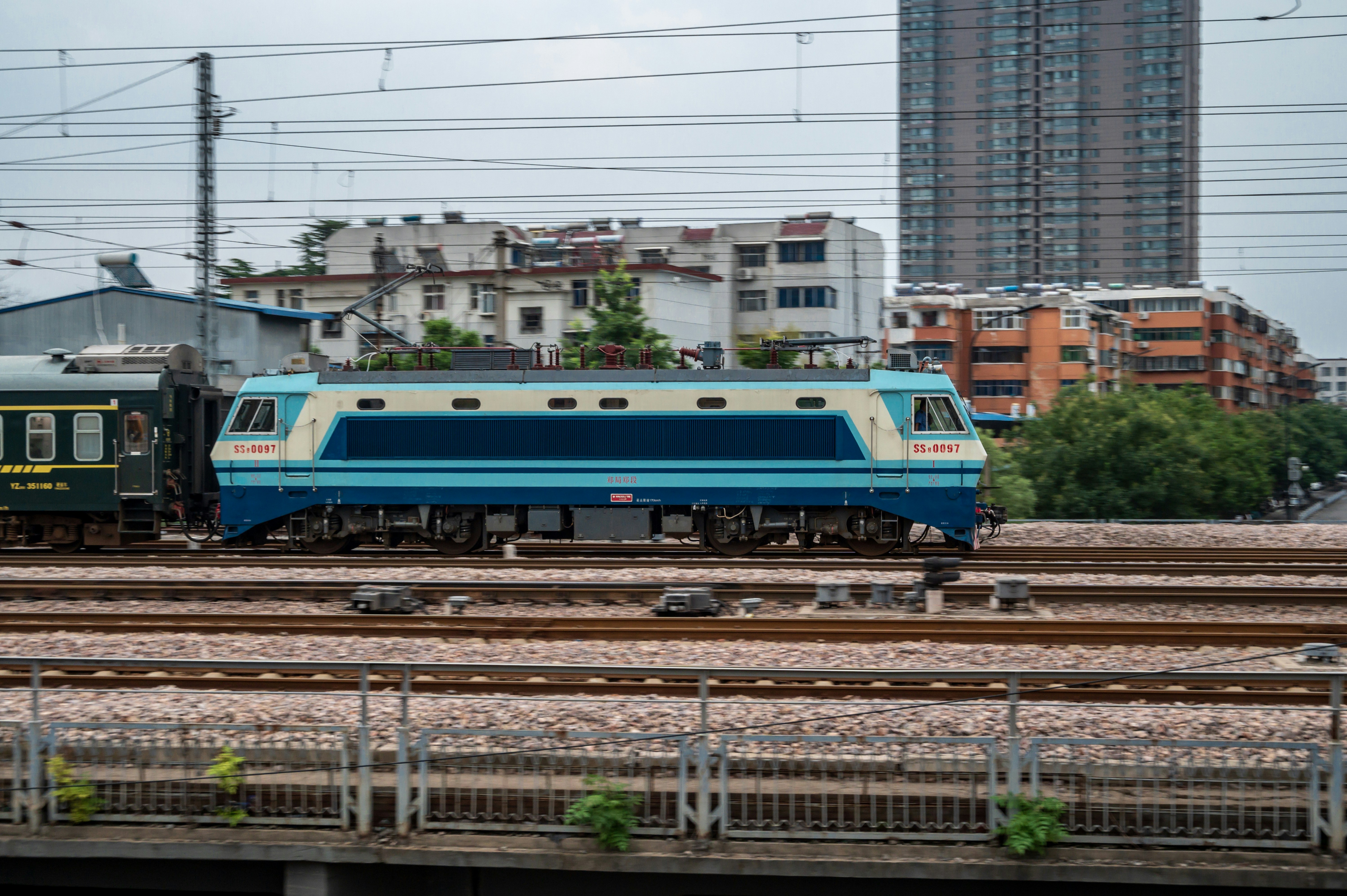 A train traveling down train tracks next to a tall building photo ...