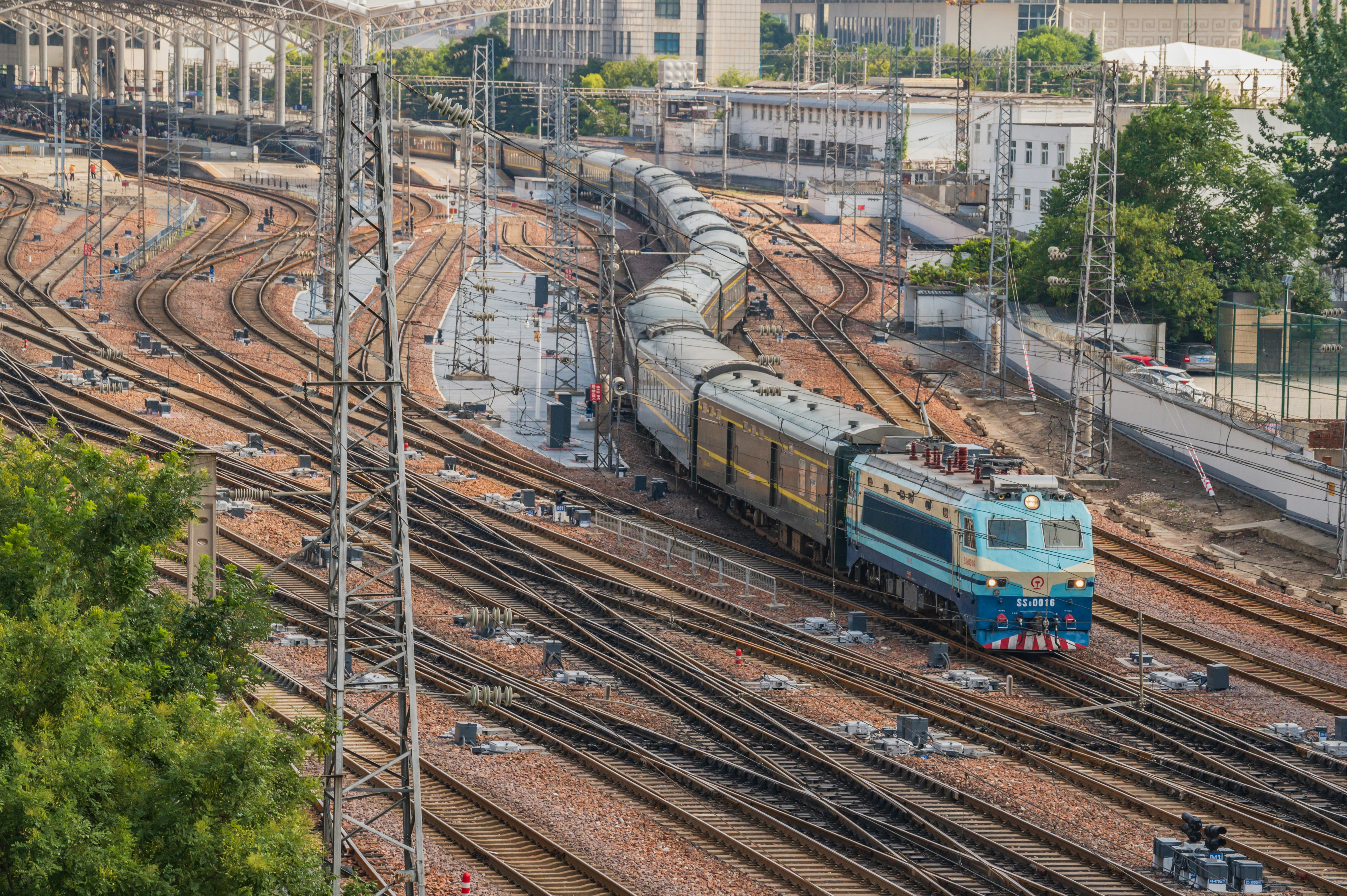A train traveling down train tracks next to tall buildings photo – Free ...