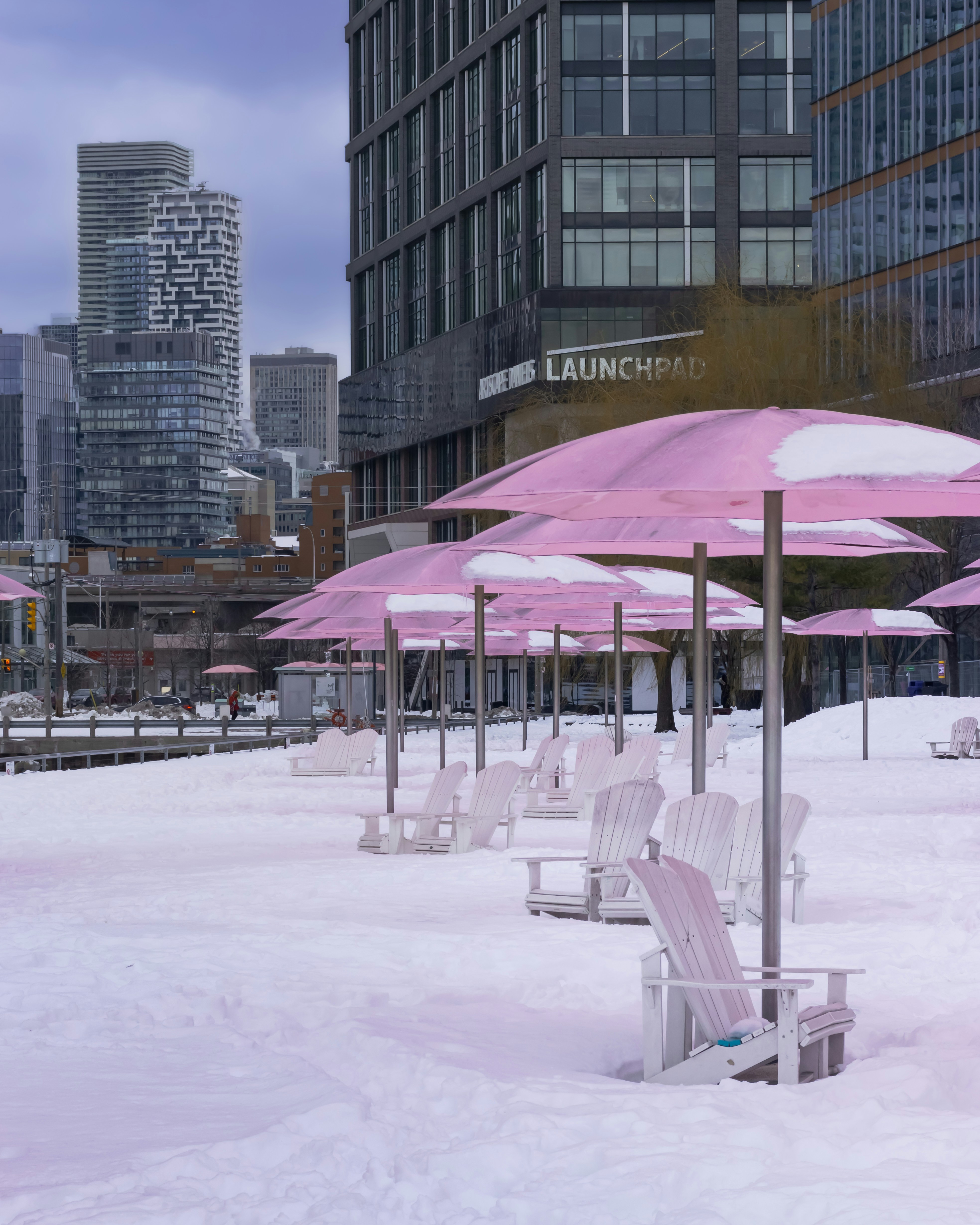 Pink Umbrellas on Snow: Urban Winter Seating by the Waterfront