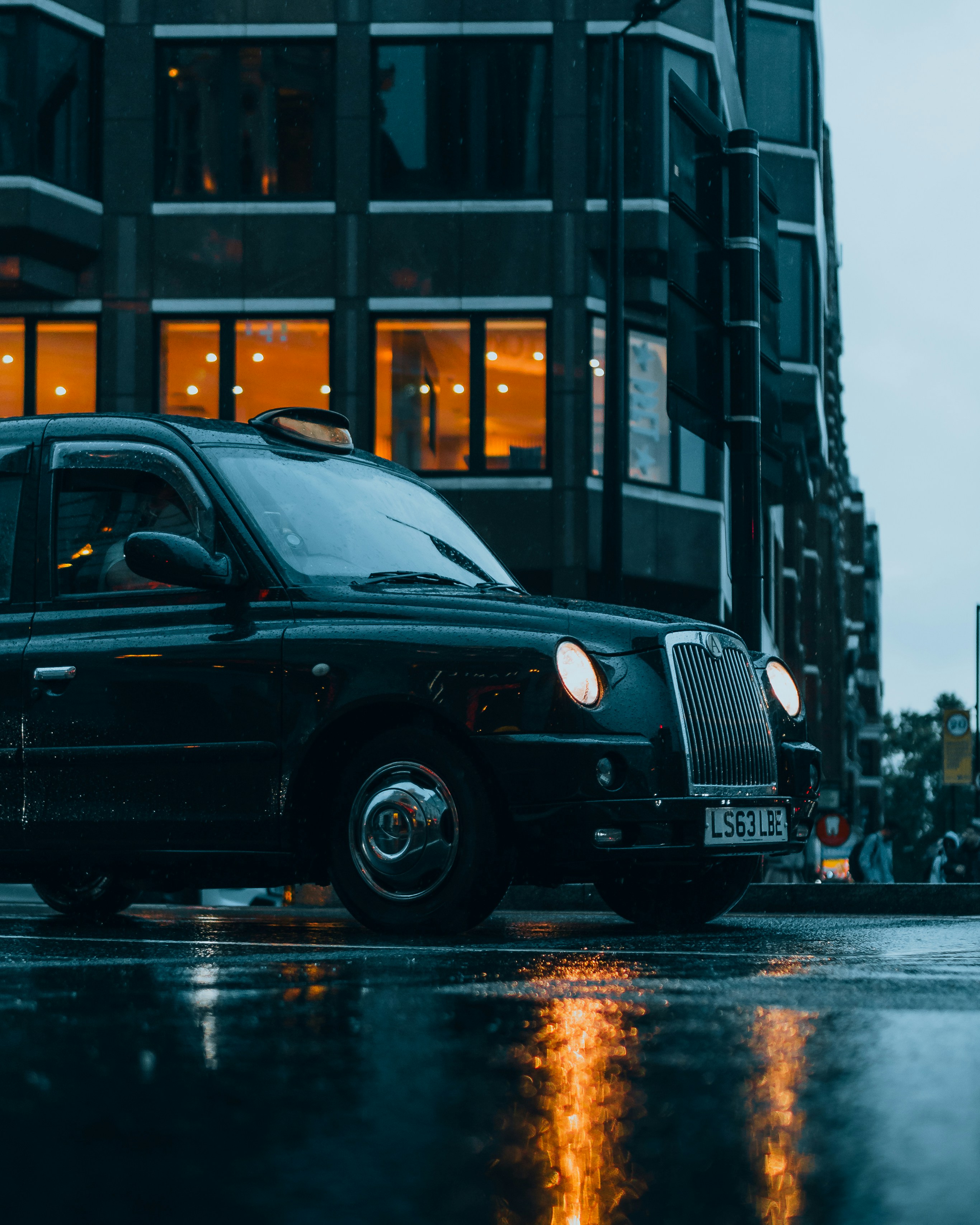 A black taxi cab driving down a street next to tall buildings photo ...