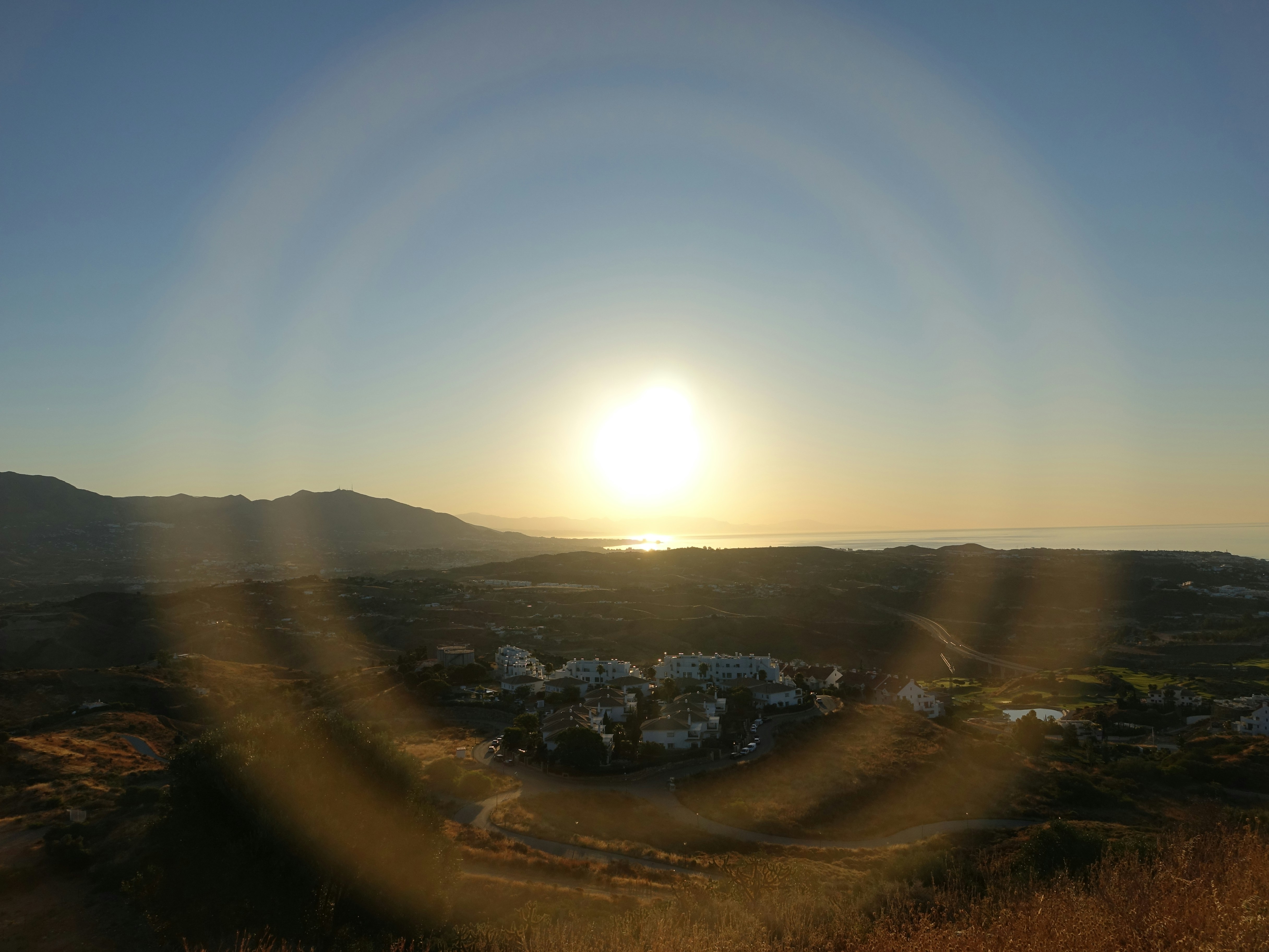 Concentric Sun Rings Over a Hilltop Village at Sunset