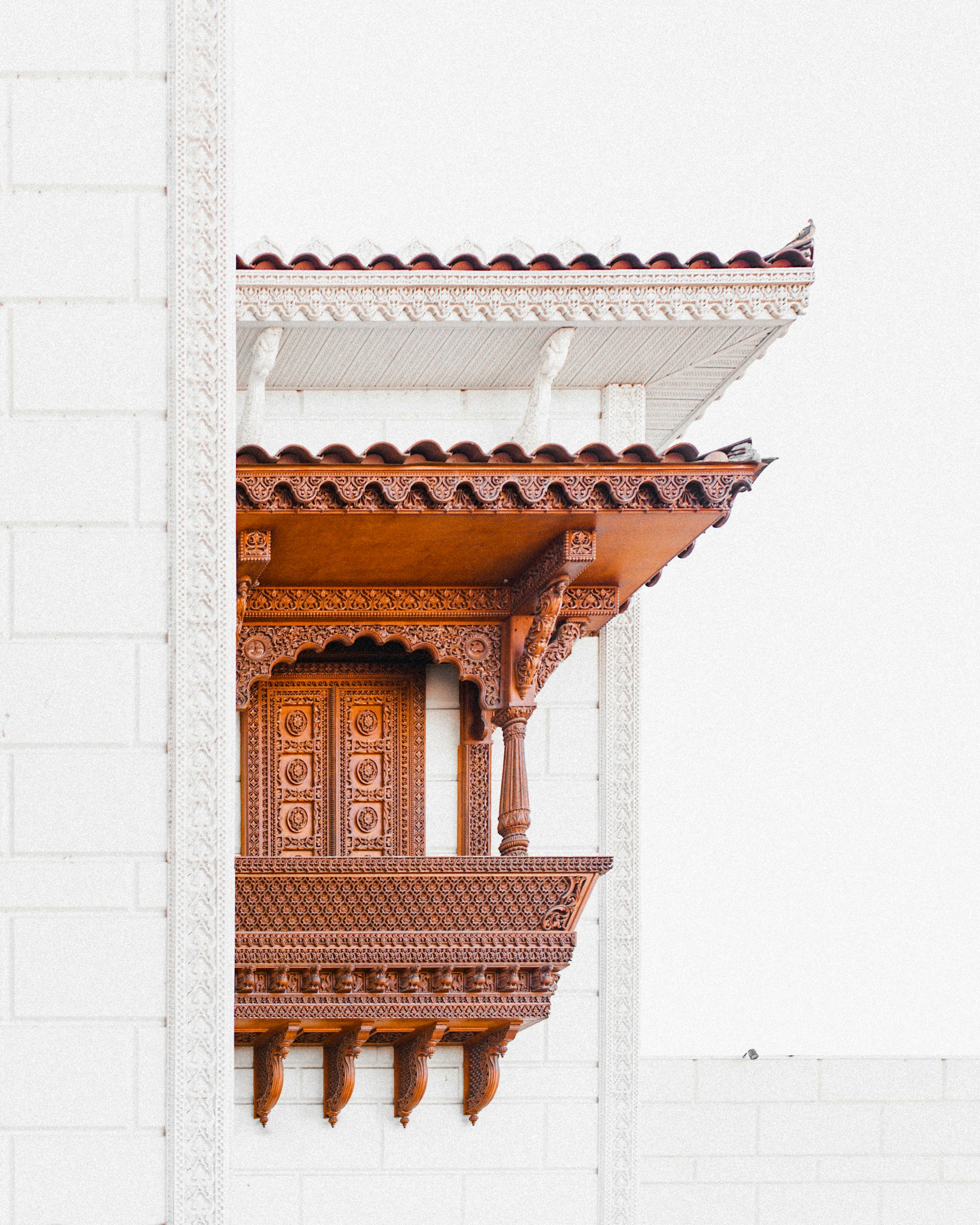 Sunlit Jharokha: Carved Balcony Emerges from a White Facade