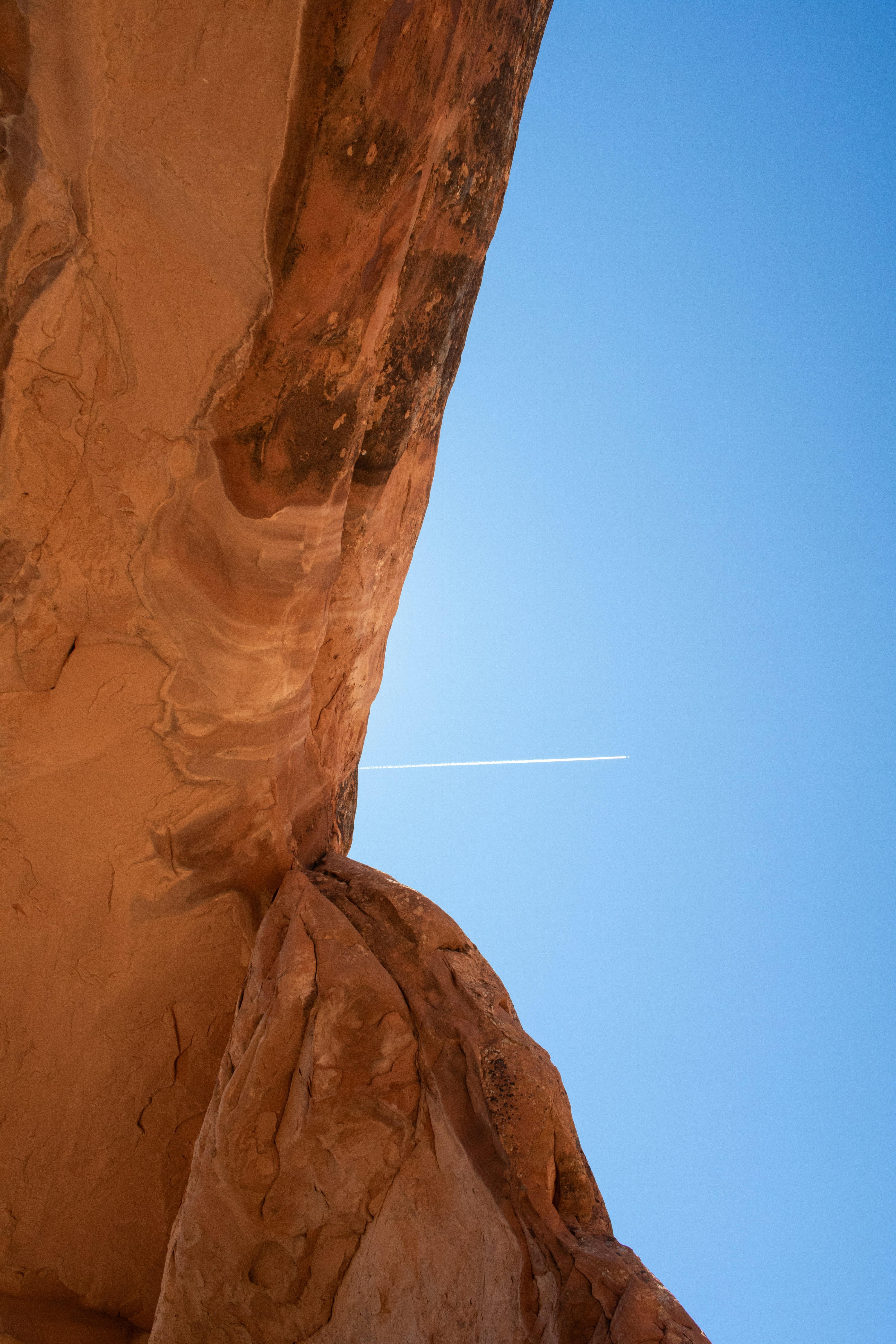 Crimson Cliffs Under a Blue Expanse, Crossed by a Silent Contrail