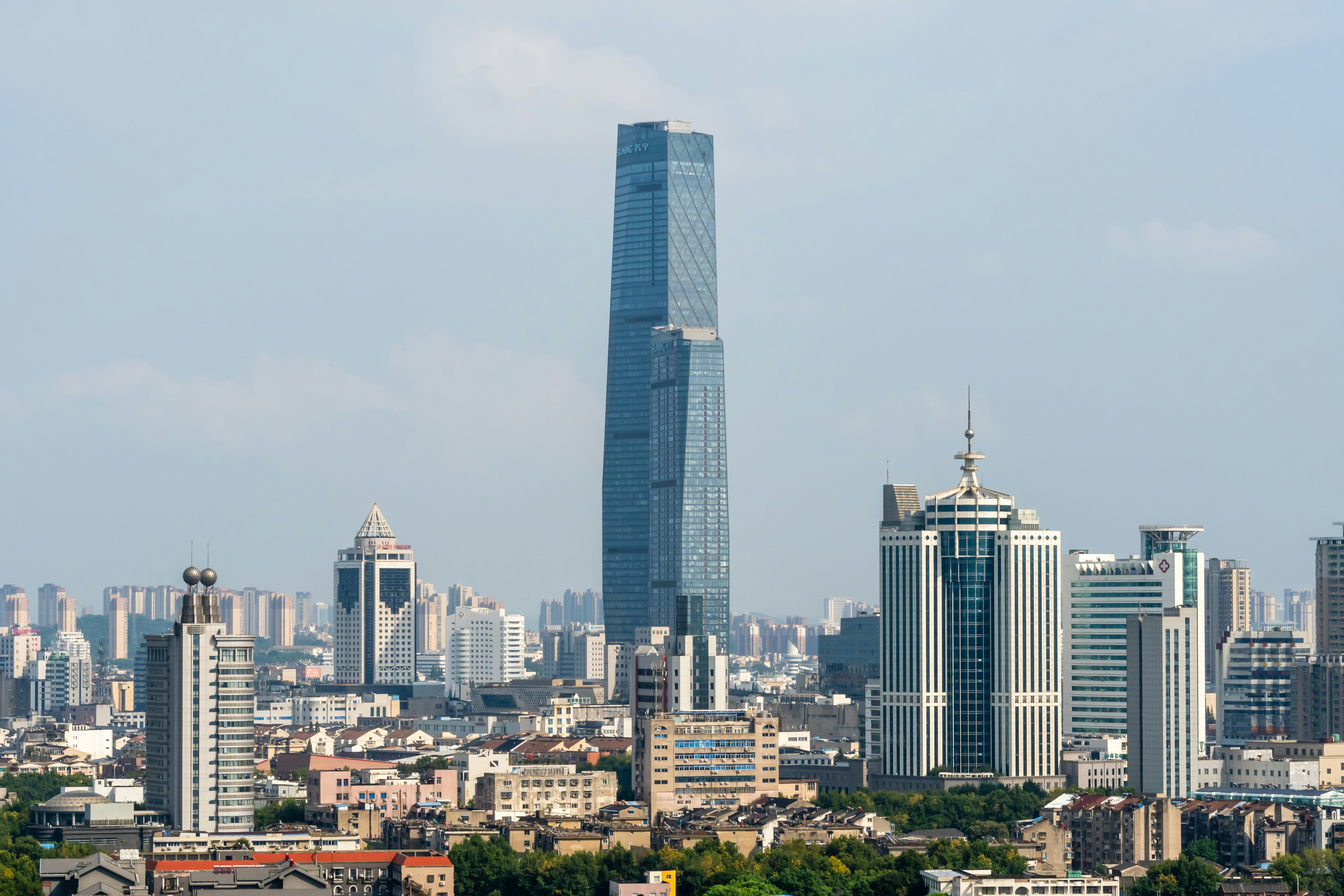 A panoramic view of a bustling city skyline featuring towering skyscrapers, including a prominent high-rise structure. The architectural diversity highlights modern urban development.