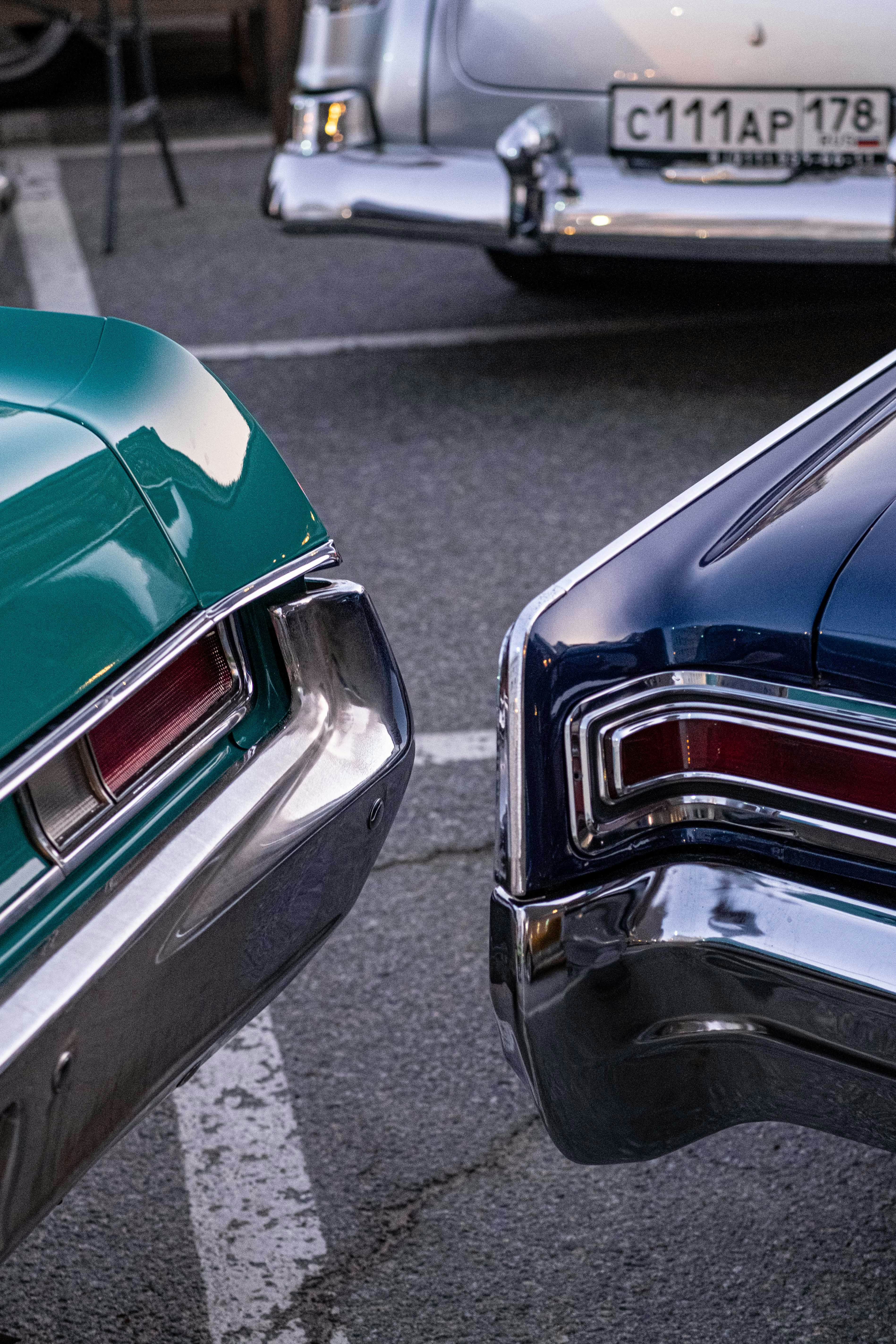 Chrome Confluence: Two vintage tail fins meet in a sunlit parking lot