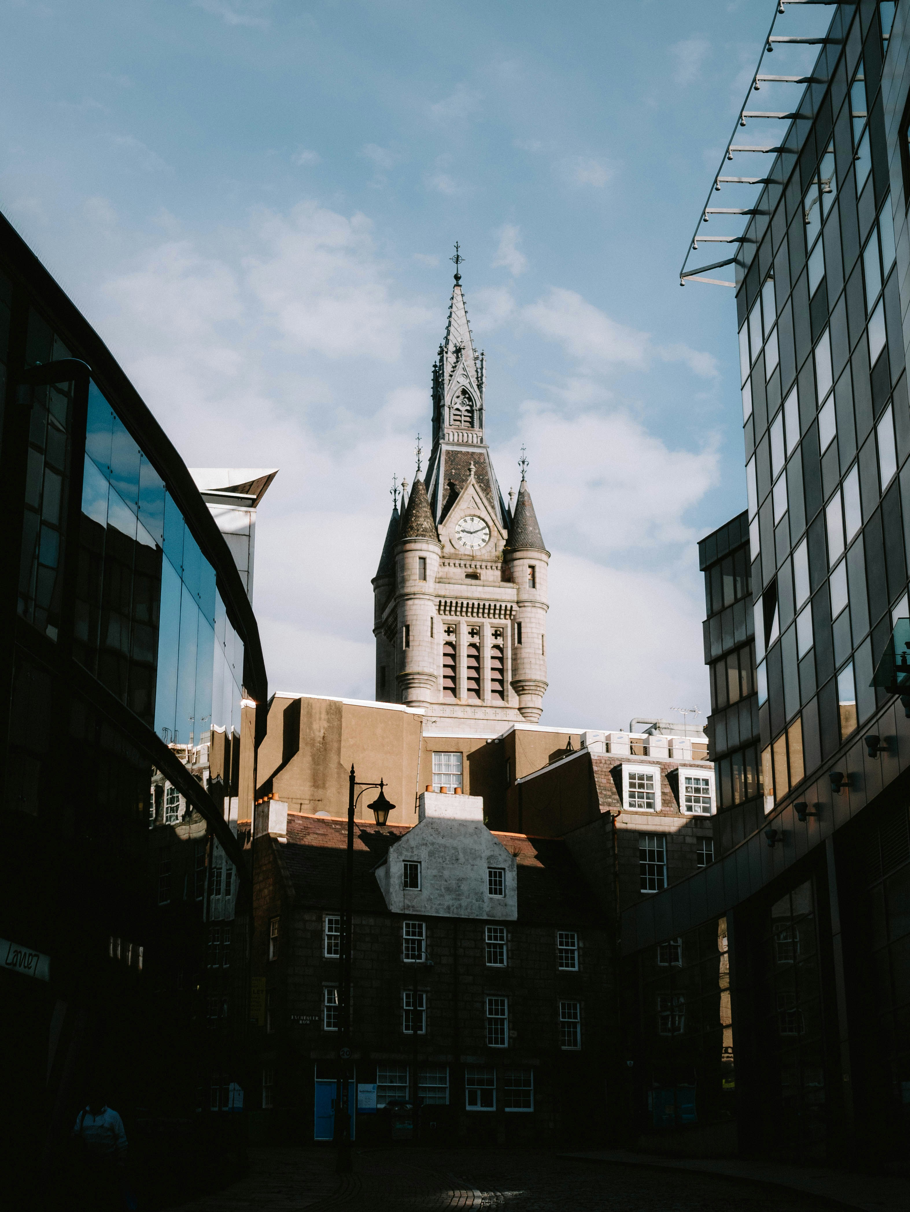 A clock tower towering over a city next to tall buildings photo – Free ...