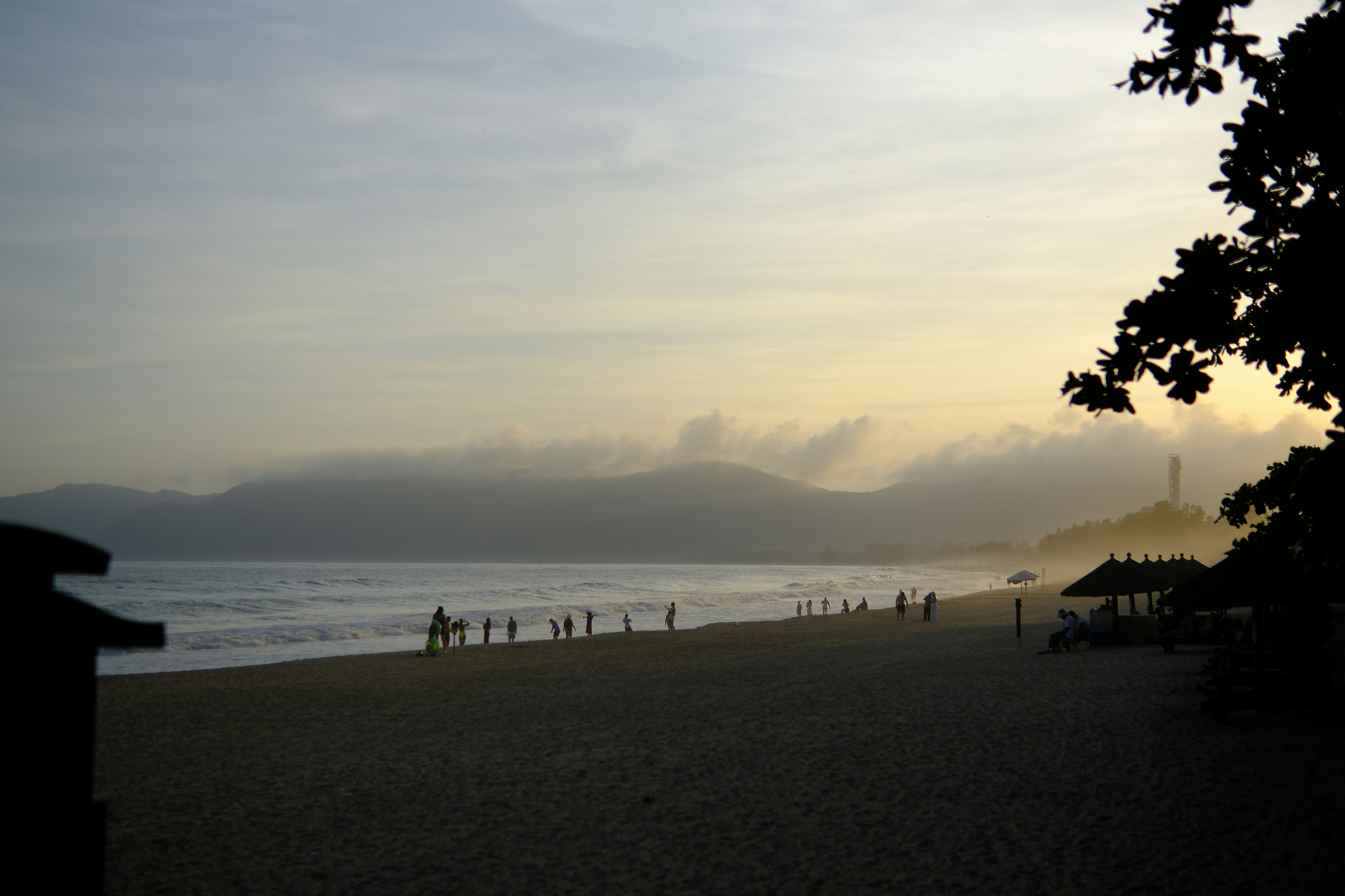 Sunset Silhouettes on a Quiet Beach with Distant Ridge and Pavilion
