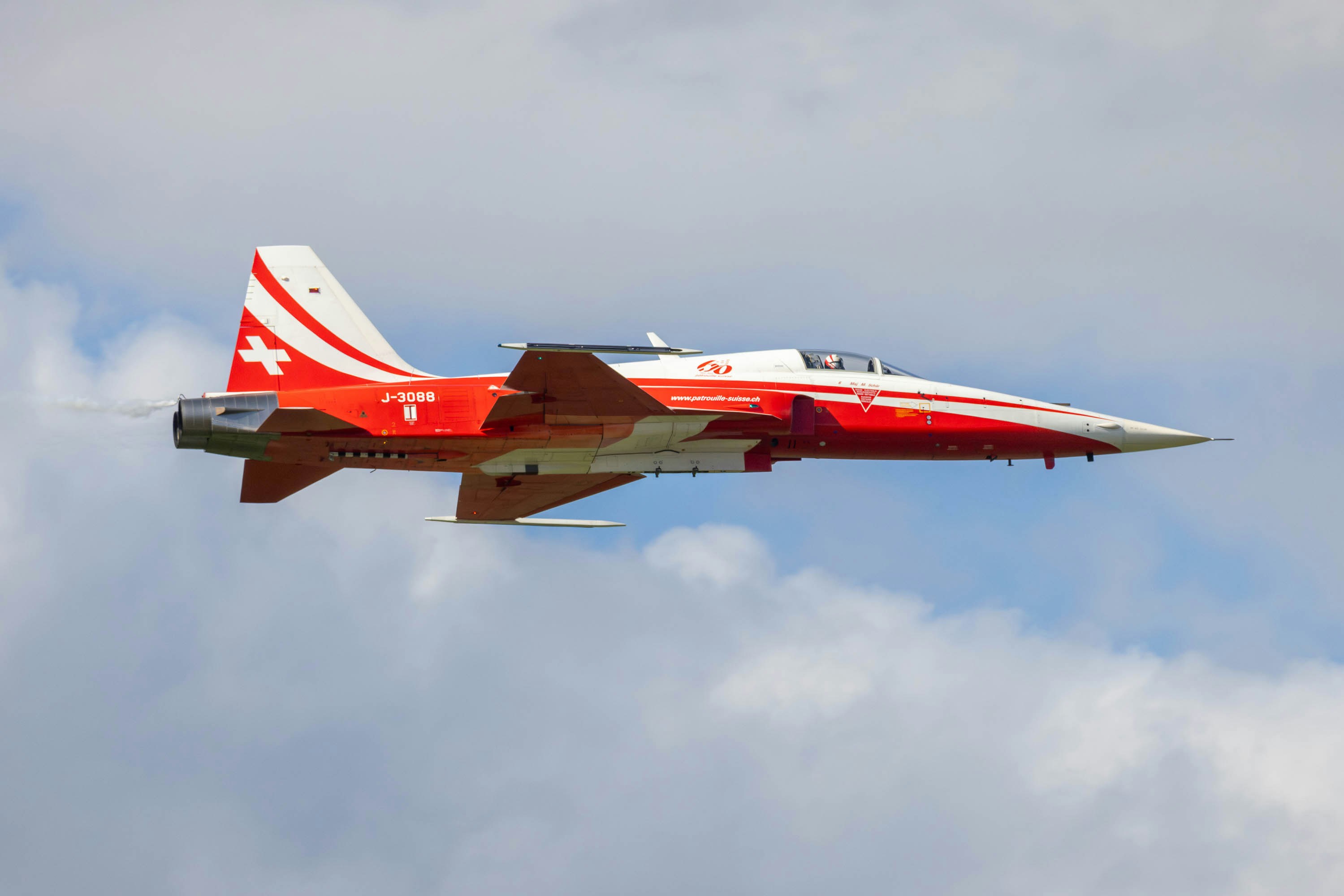 A red and white jet flying through a cloudy sky photo – Free ...