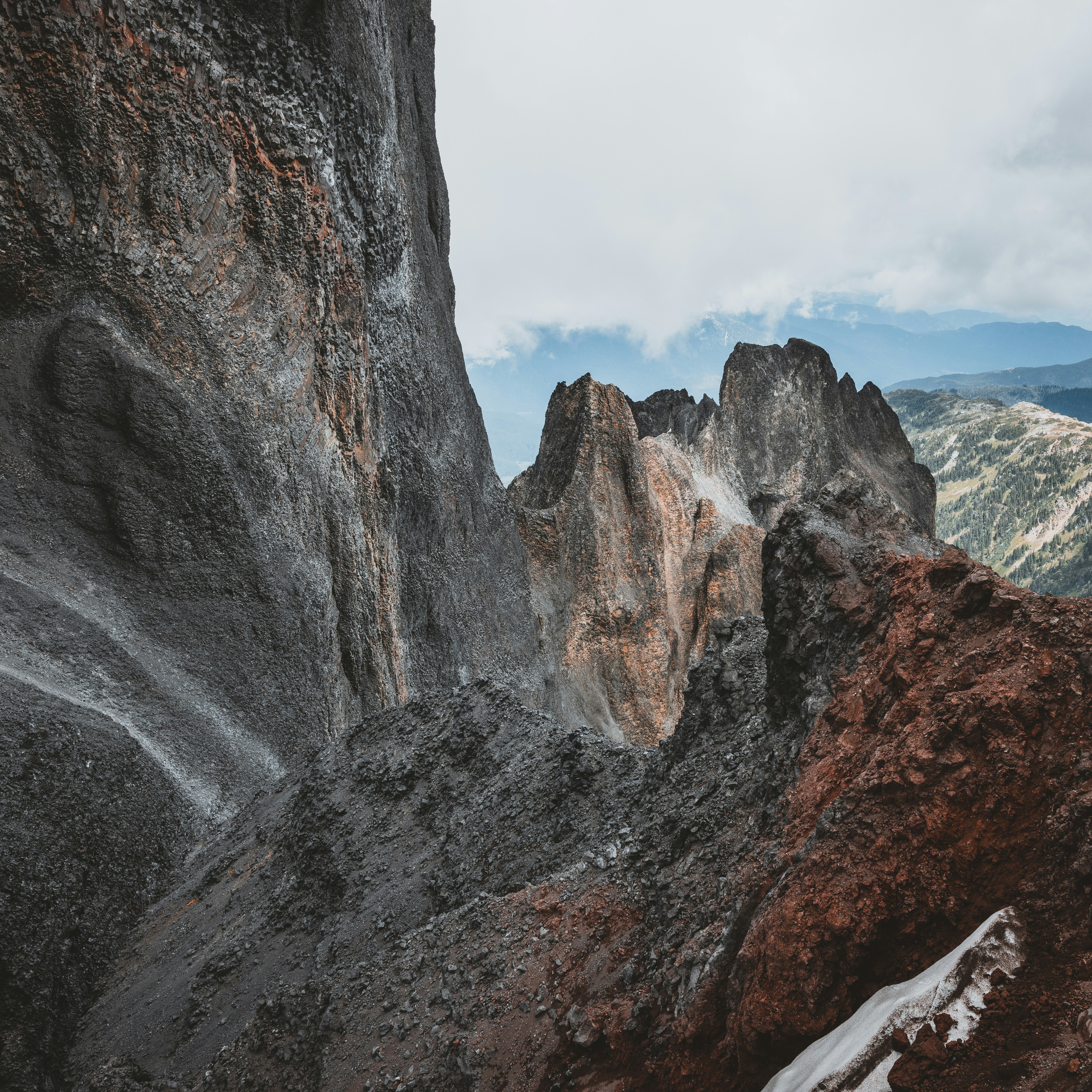 Dramatic rocky outcrops rise sharply against a cloudy sky, showcasing the rugged beauty of a mountainous landscape.