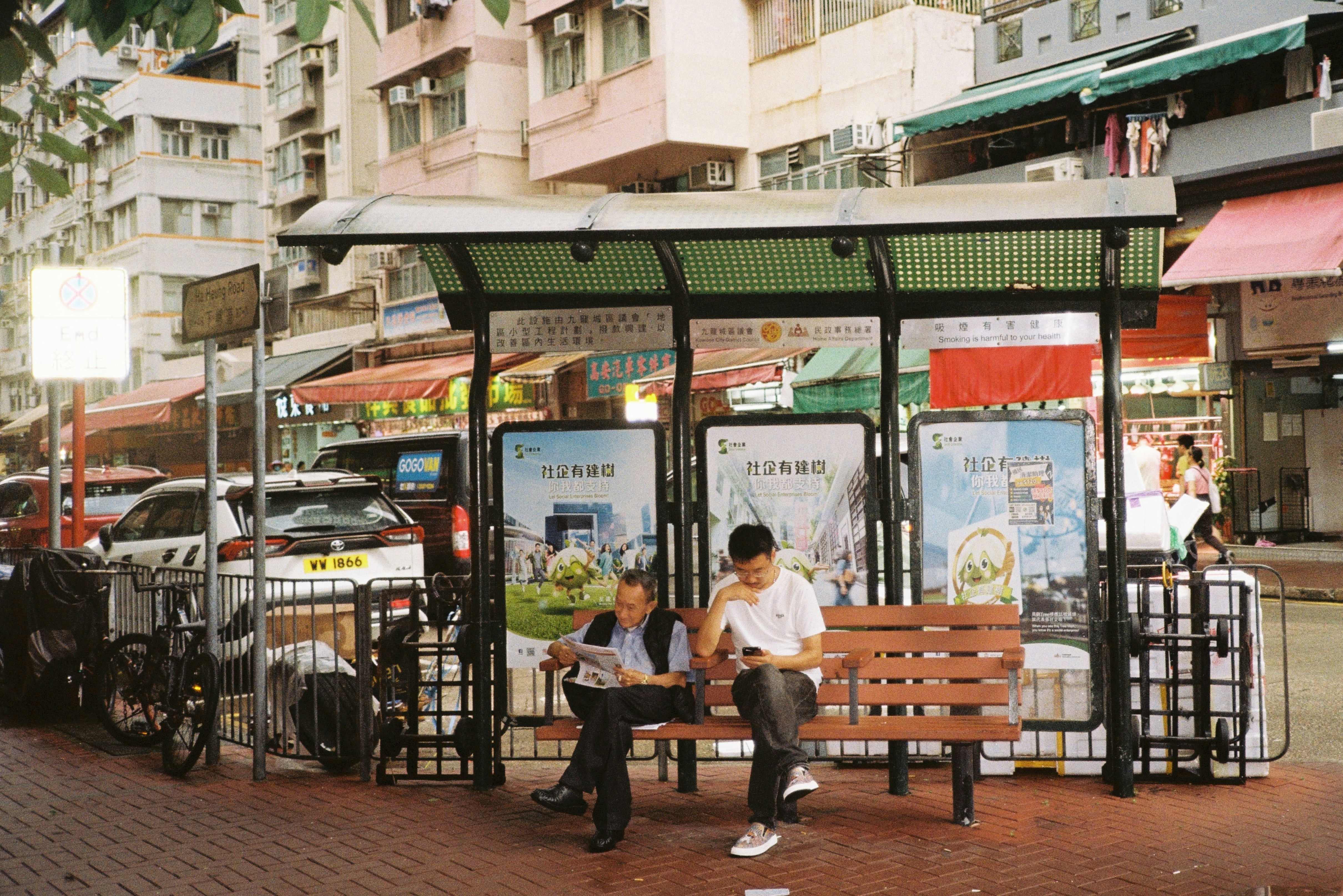 A man sitting on a bench in front of a bus stop photo – Free Film ...