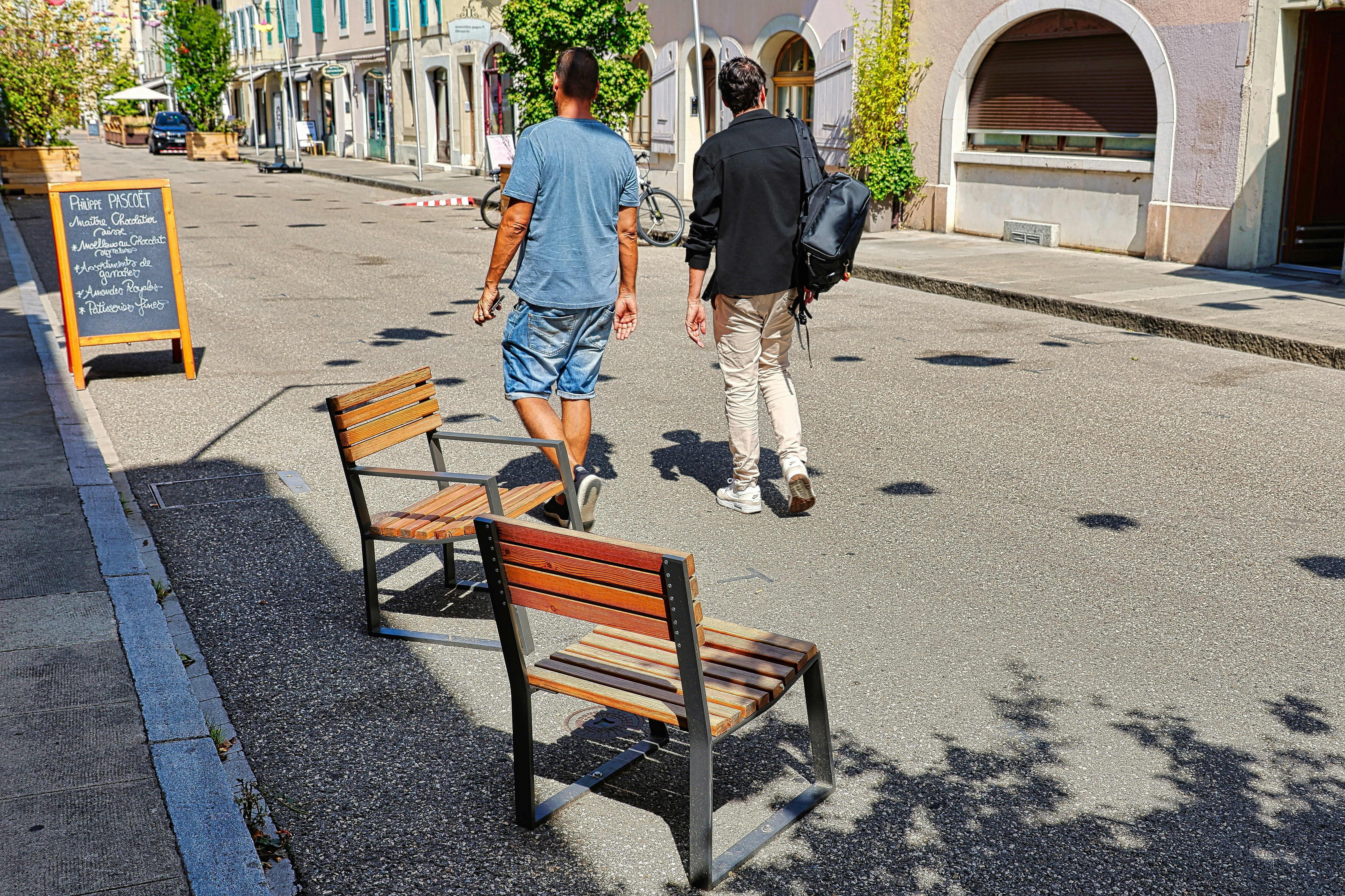 Sunlit Crossing: Two Pedestrians Move Through a Quiet Street